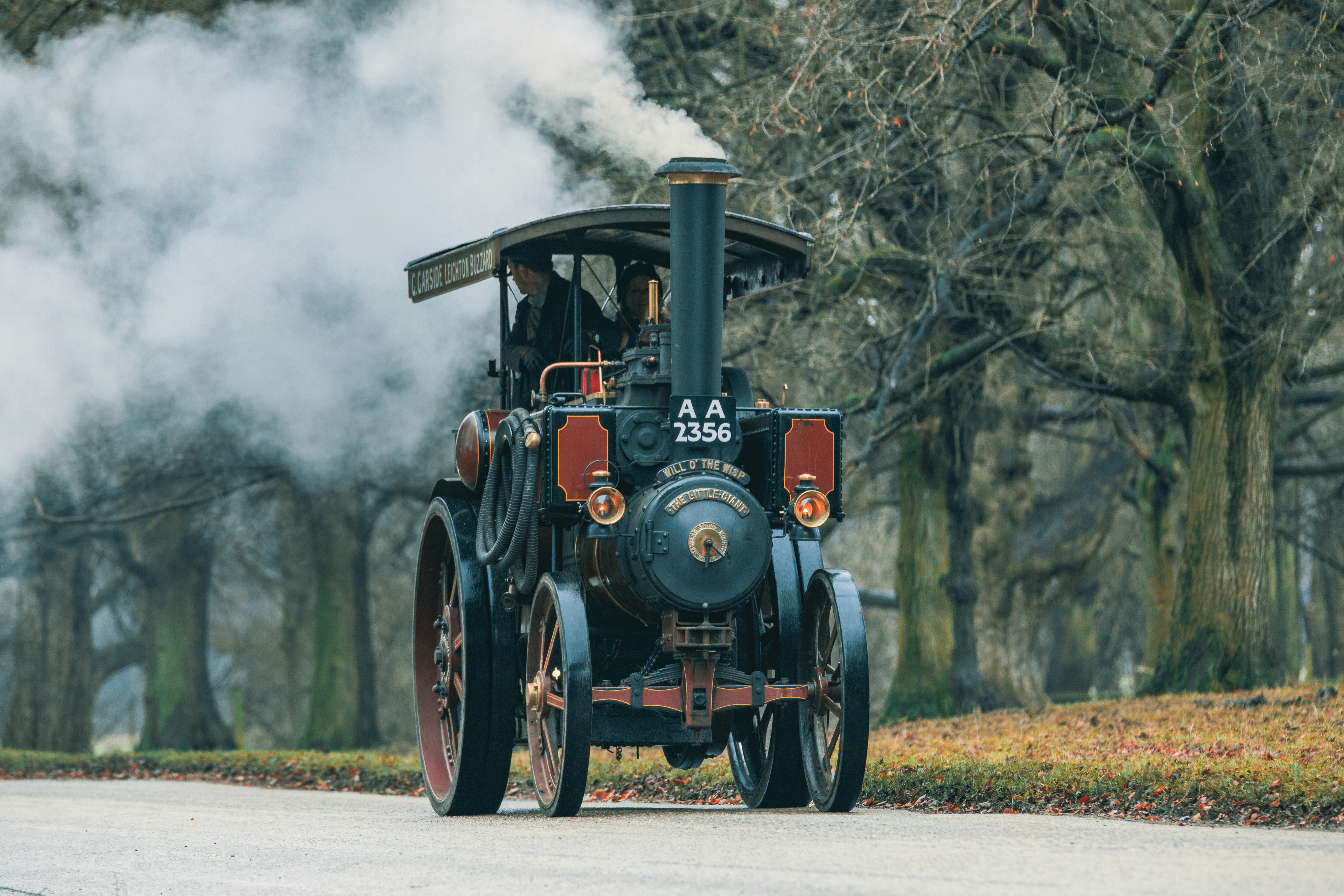 150 year old steam engine moving slowly through a country park in the United Kingdom  | classic black and brown vehicle emitting smoke