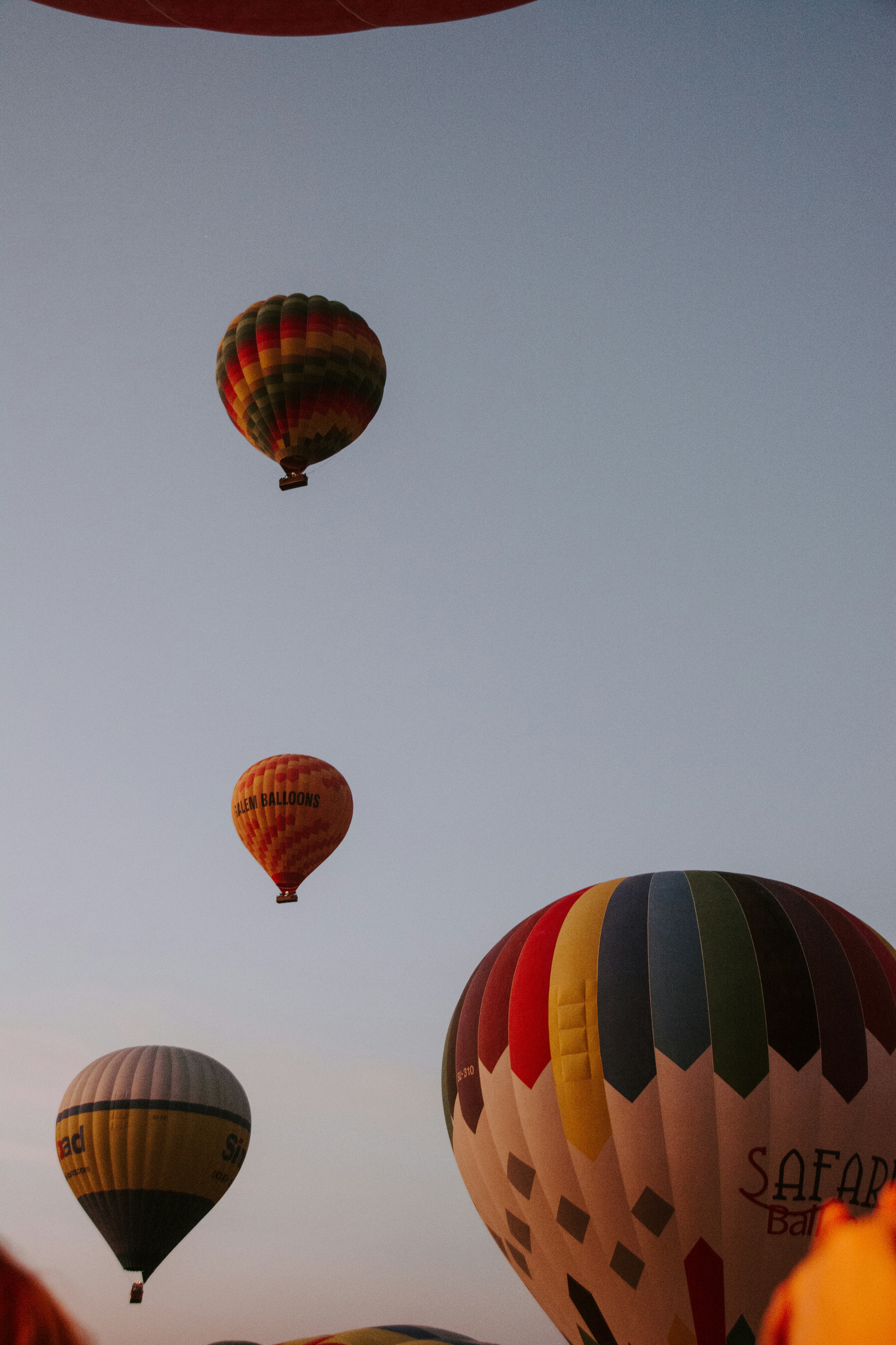 Colorful hot air balloons ascend into the twilight sky, creating a vibrant spectacle against the fading light.