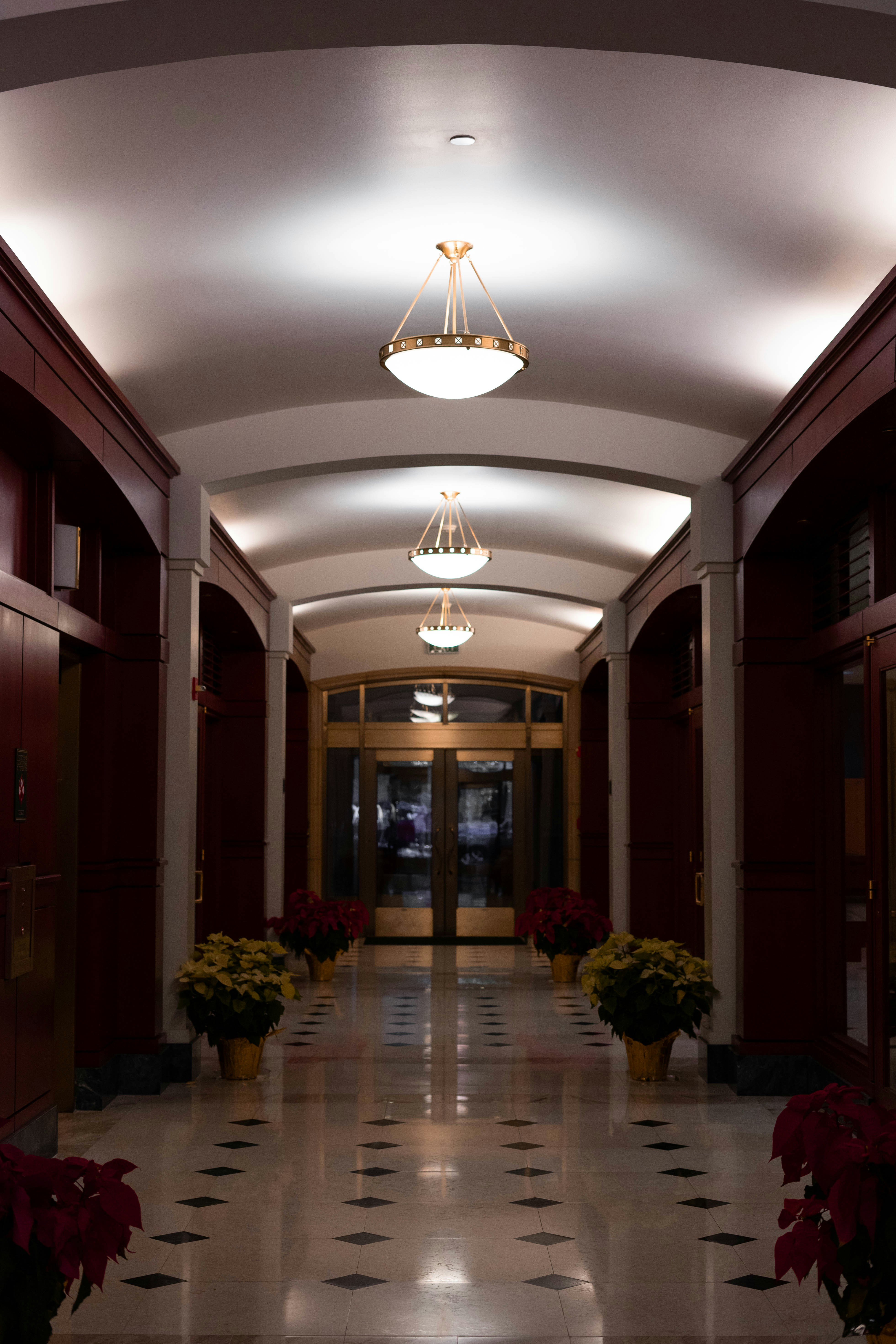 Vanishing Hallway: Haloed Chandeliers and a Glass-Front Exit