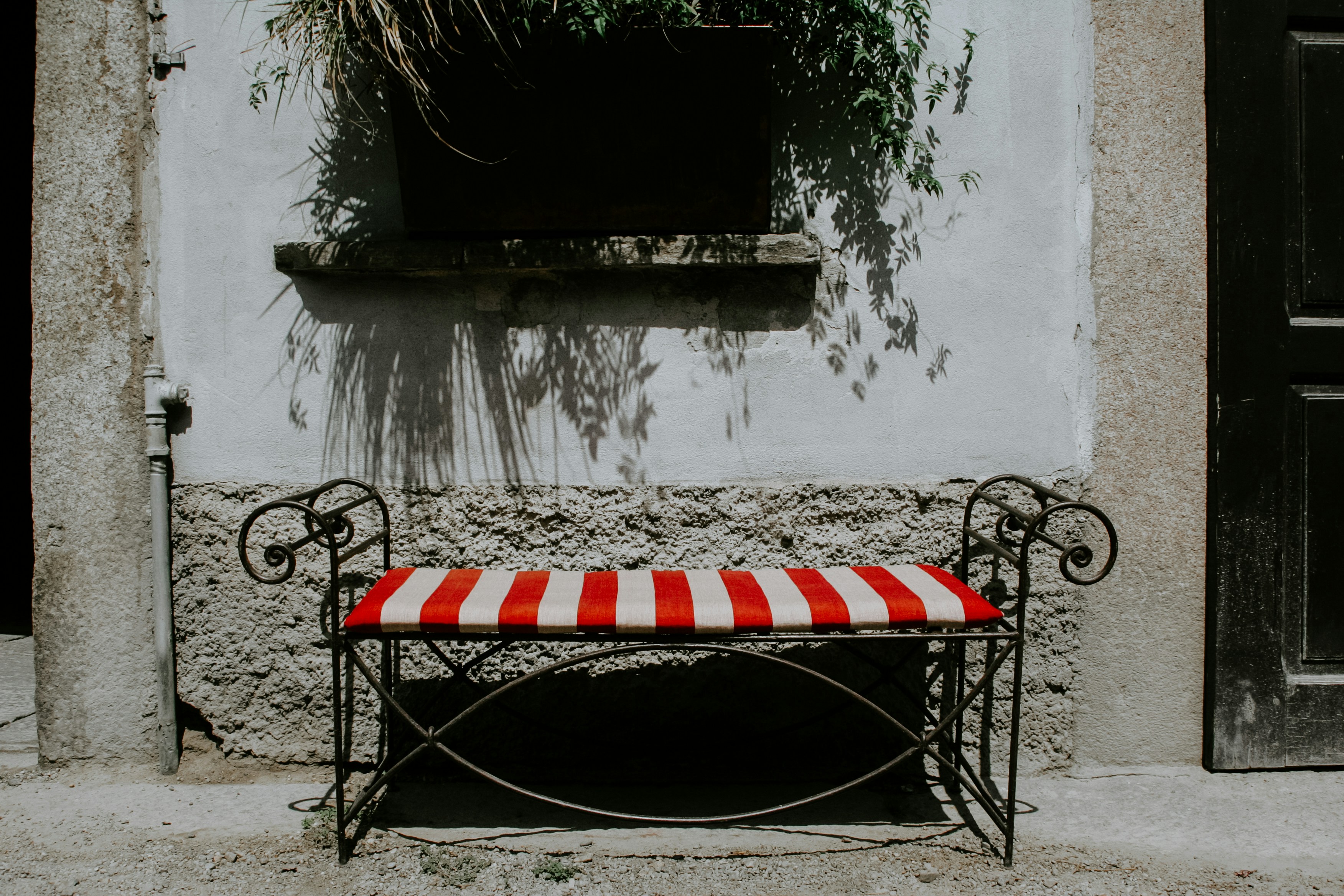 Red-Striped Bench Beneath a Shadowed Window