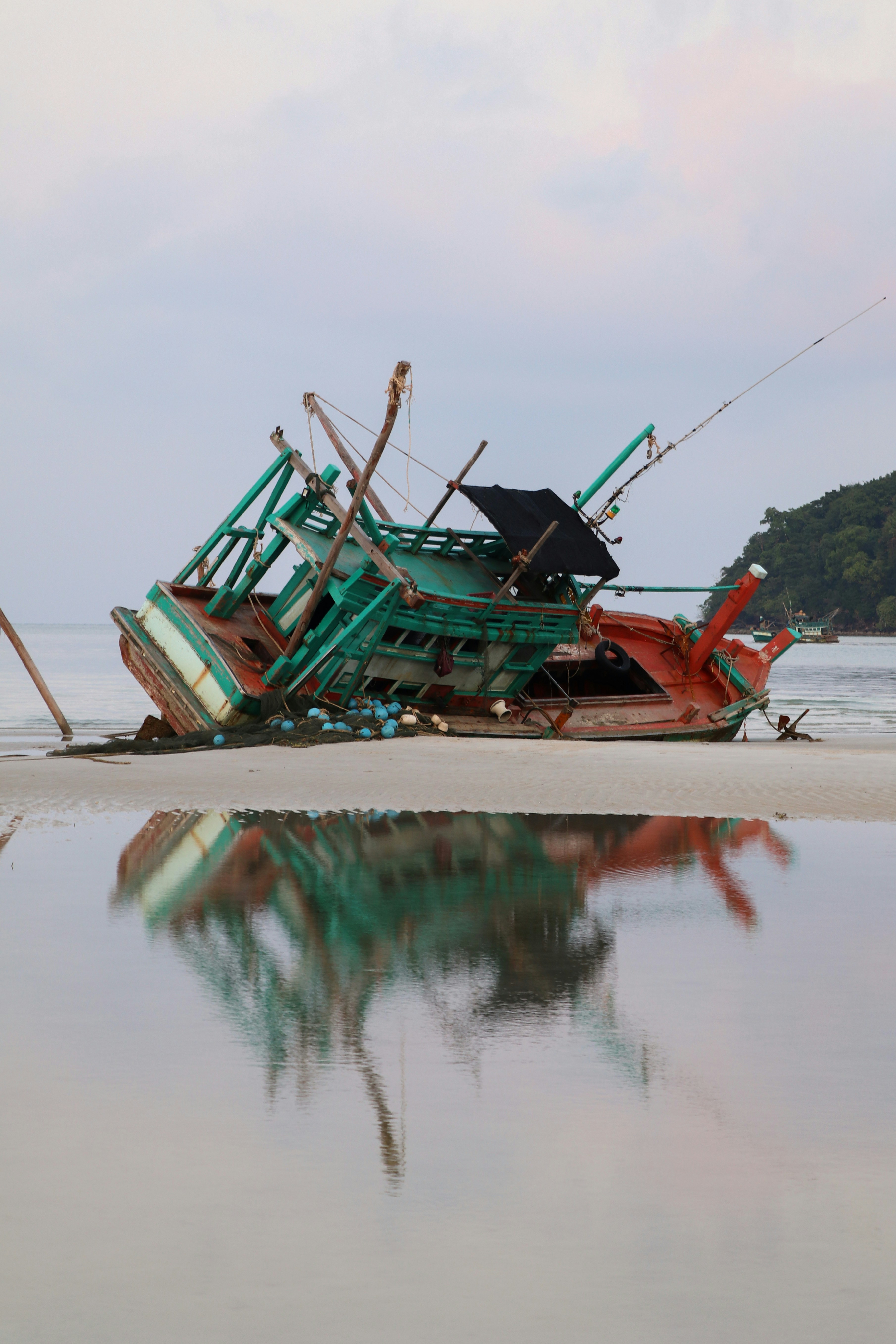 Sunken Teal and Coral Hull: A Coastal Wreck Reclaimed by Shoreline Light