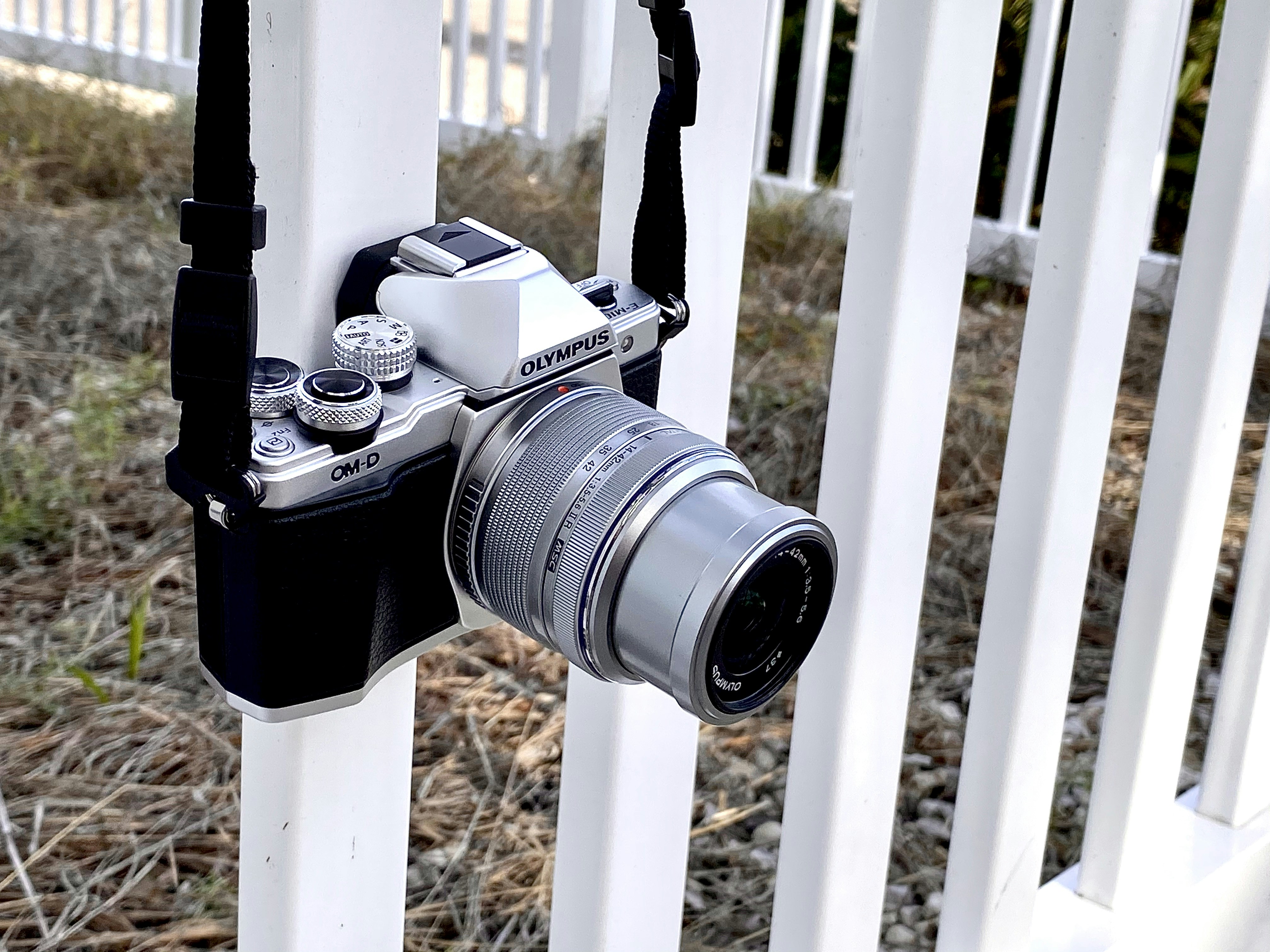 Black and silver DSLR camera hanging from a white metal fence photo ...