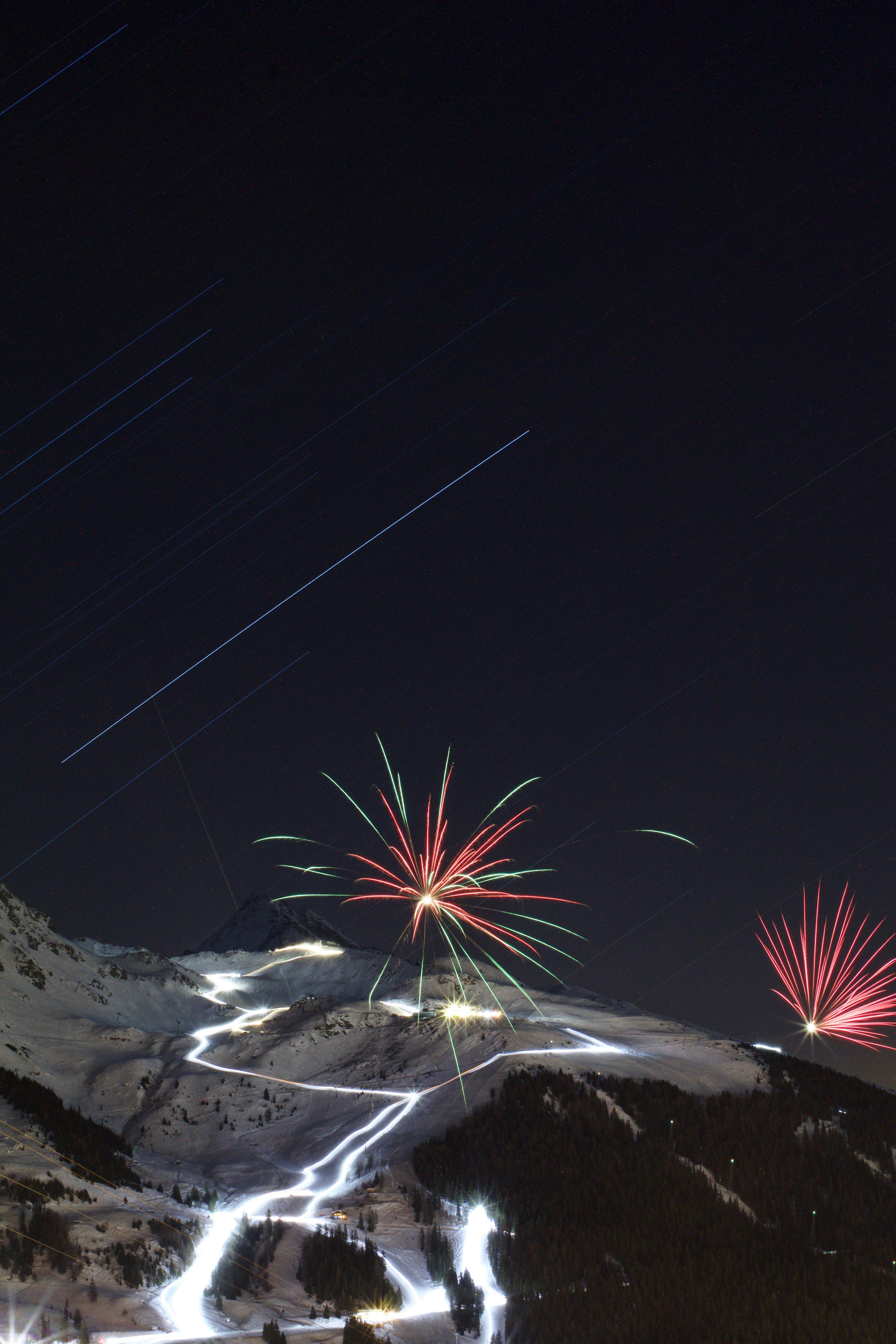 Crimson Fireworks Over a Winding Snow-Swept Trail Beneath Star Trails
