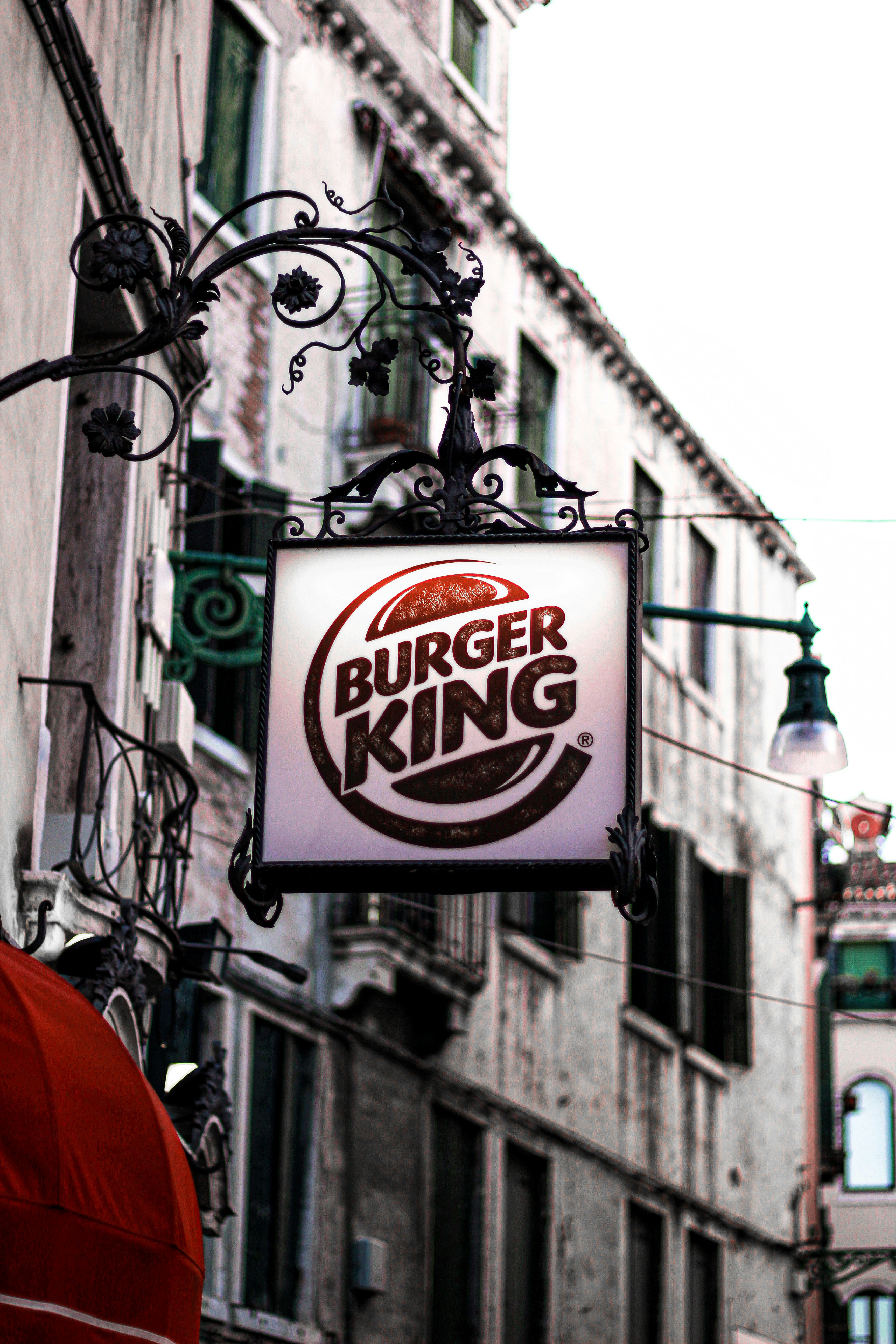 Burger King sign hanging in a narrow alleyway, blending modern branding with the historic architecture of the surrounding buildings.