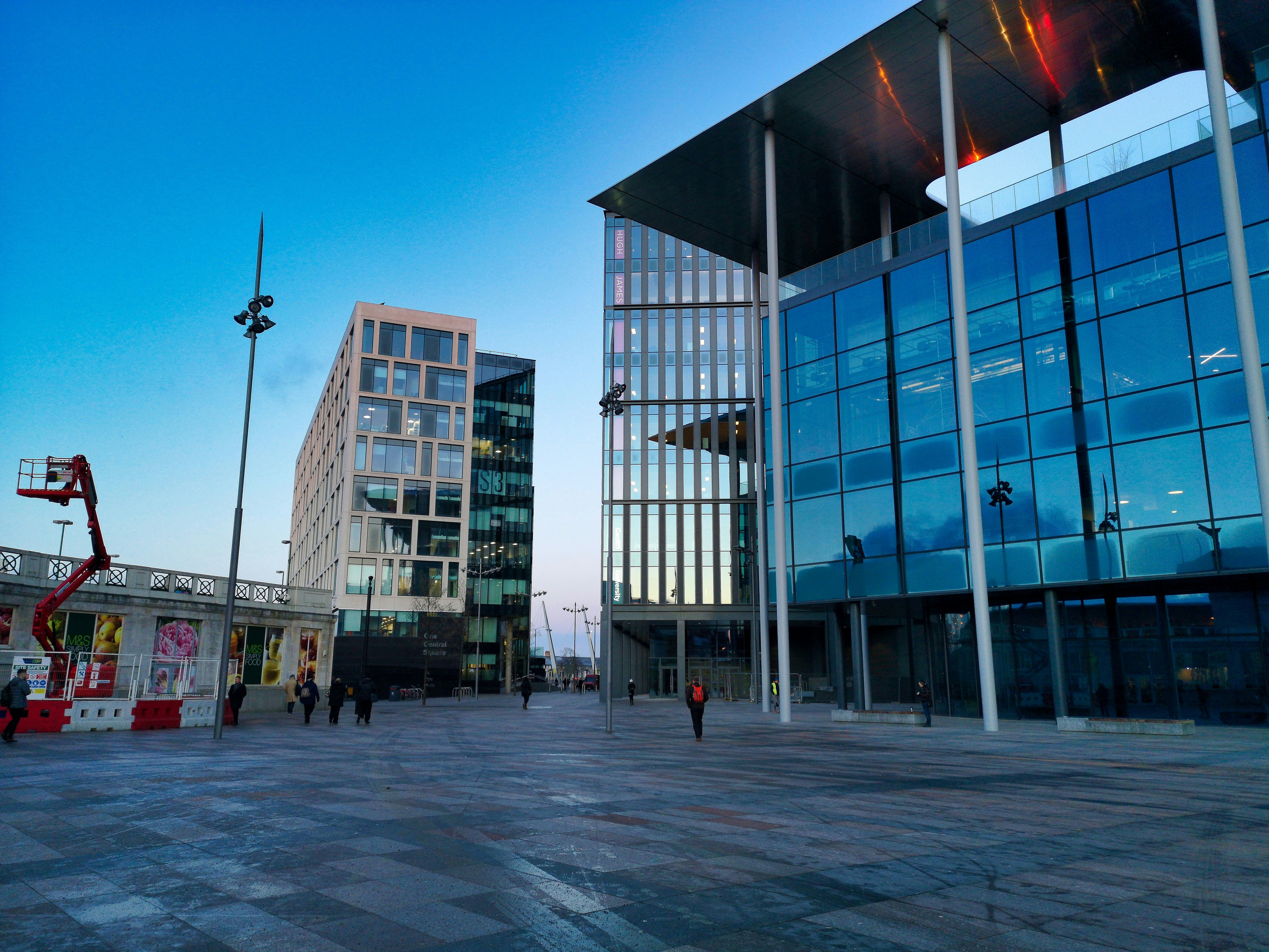 Modern glass buildings reflecting the twilight sky in an urban plaza.