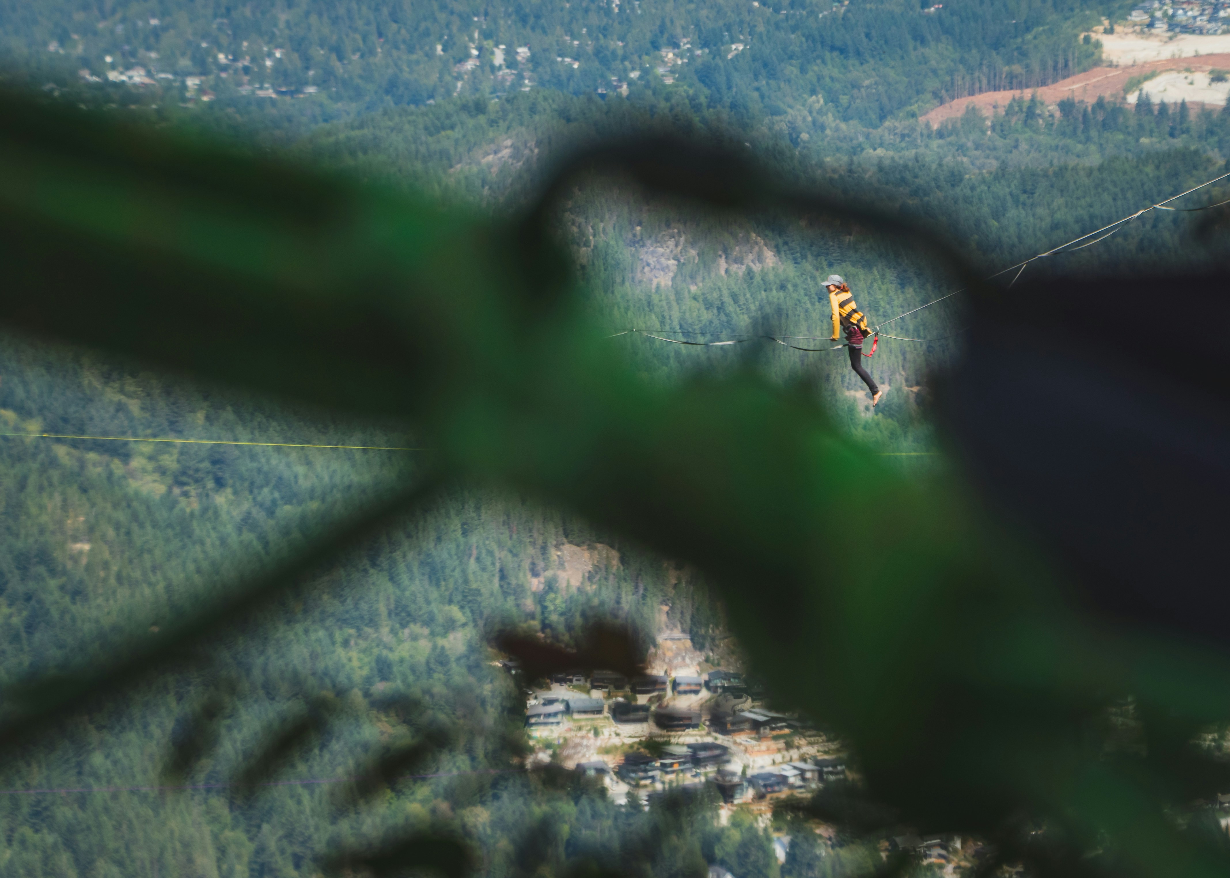 Slackline woman suspended high above the ground seen thru a Carabeaner