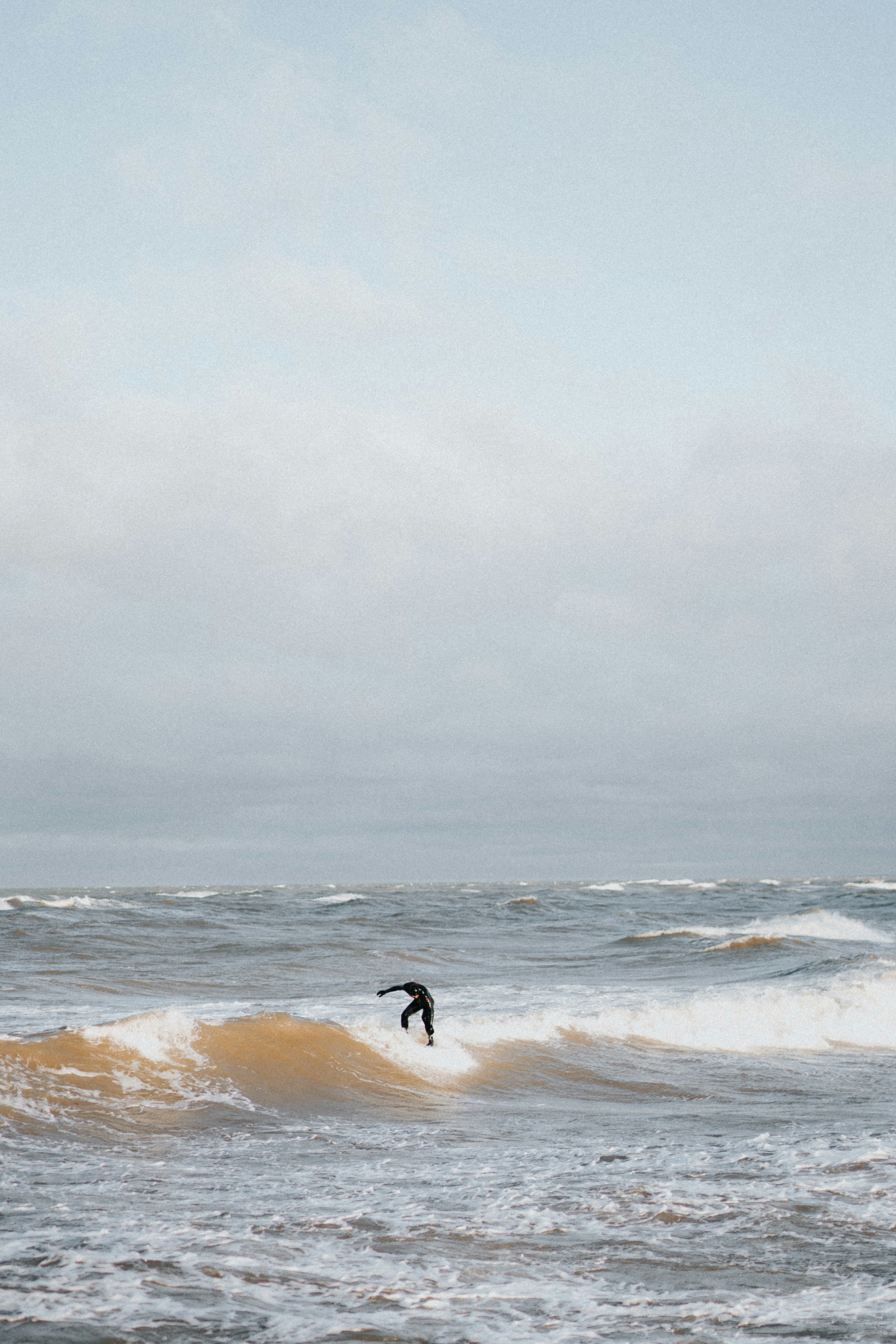 Persona surfeando en la ola del mar bajo el cielo blanco foto – Imagen ...