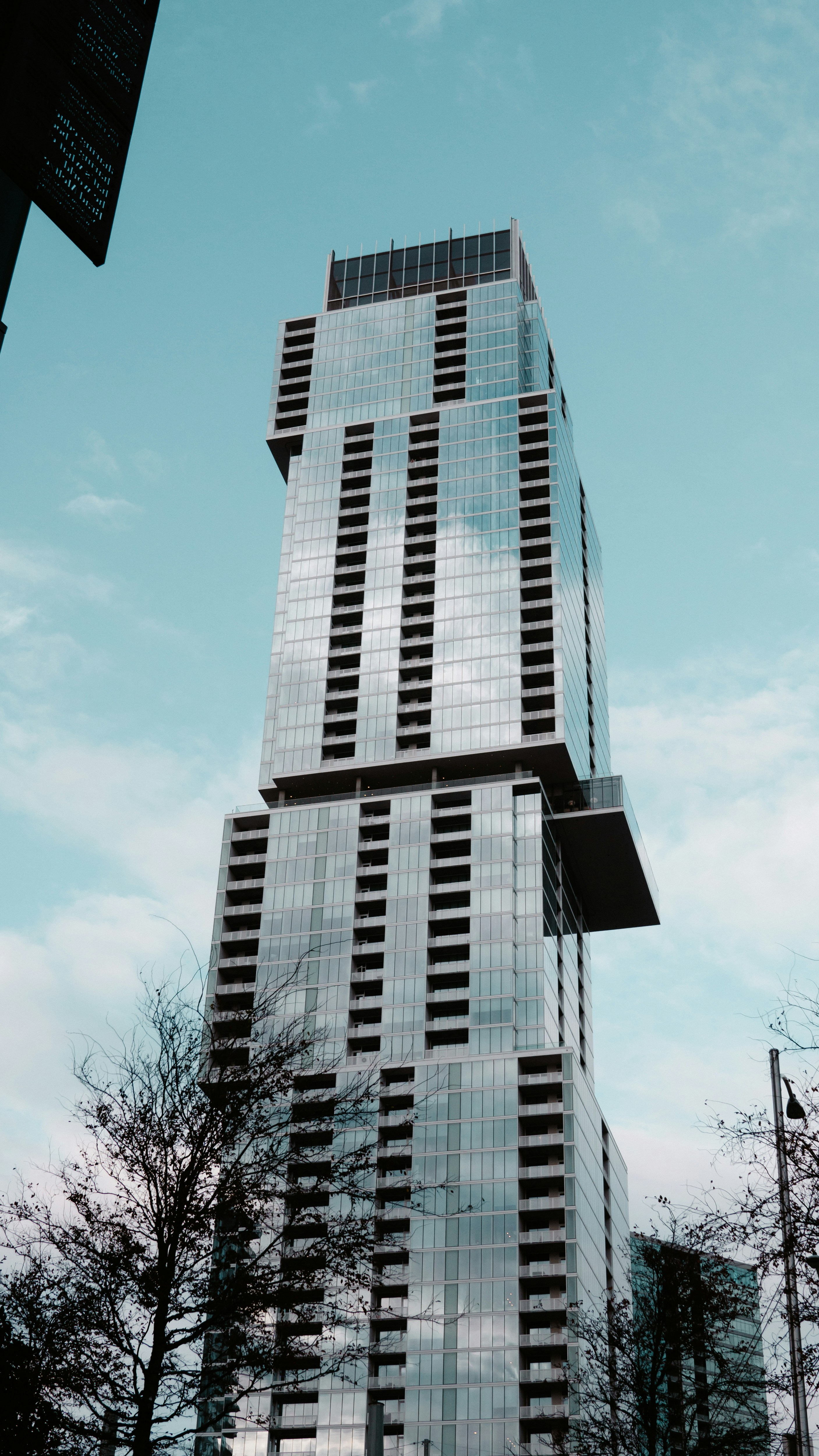 Gray high-rise building near trees under blue and white sky photo ...