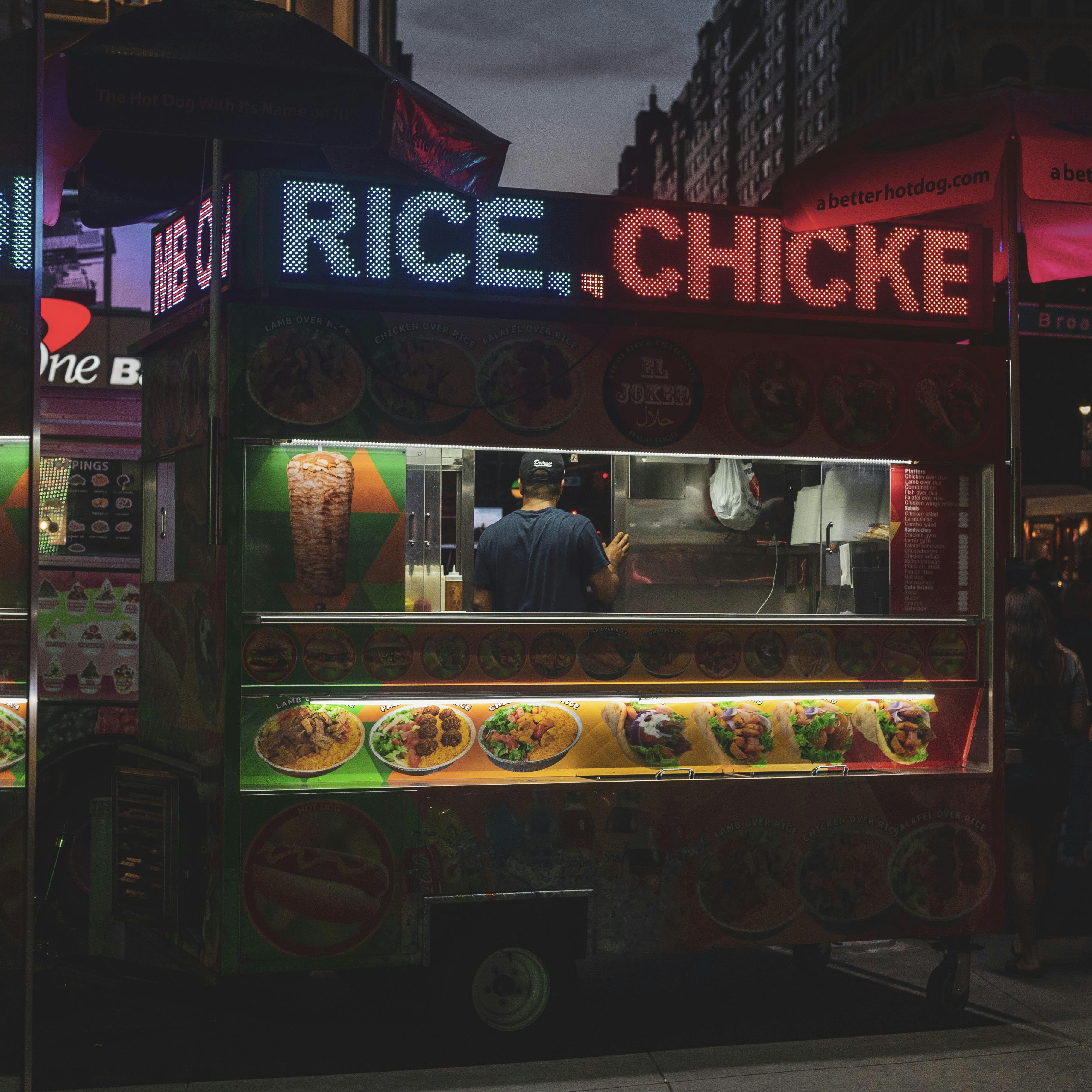 Neon Sizzle at Midnight: Night Cart Glow and a Vendor Behind Glass