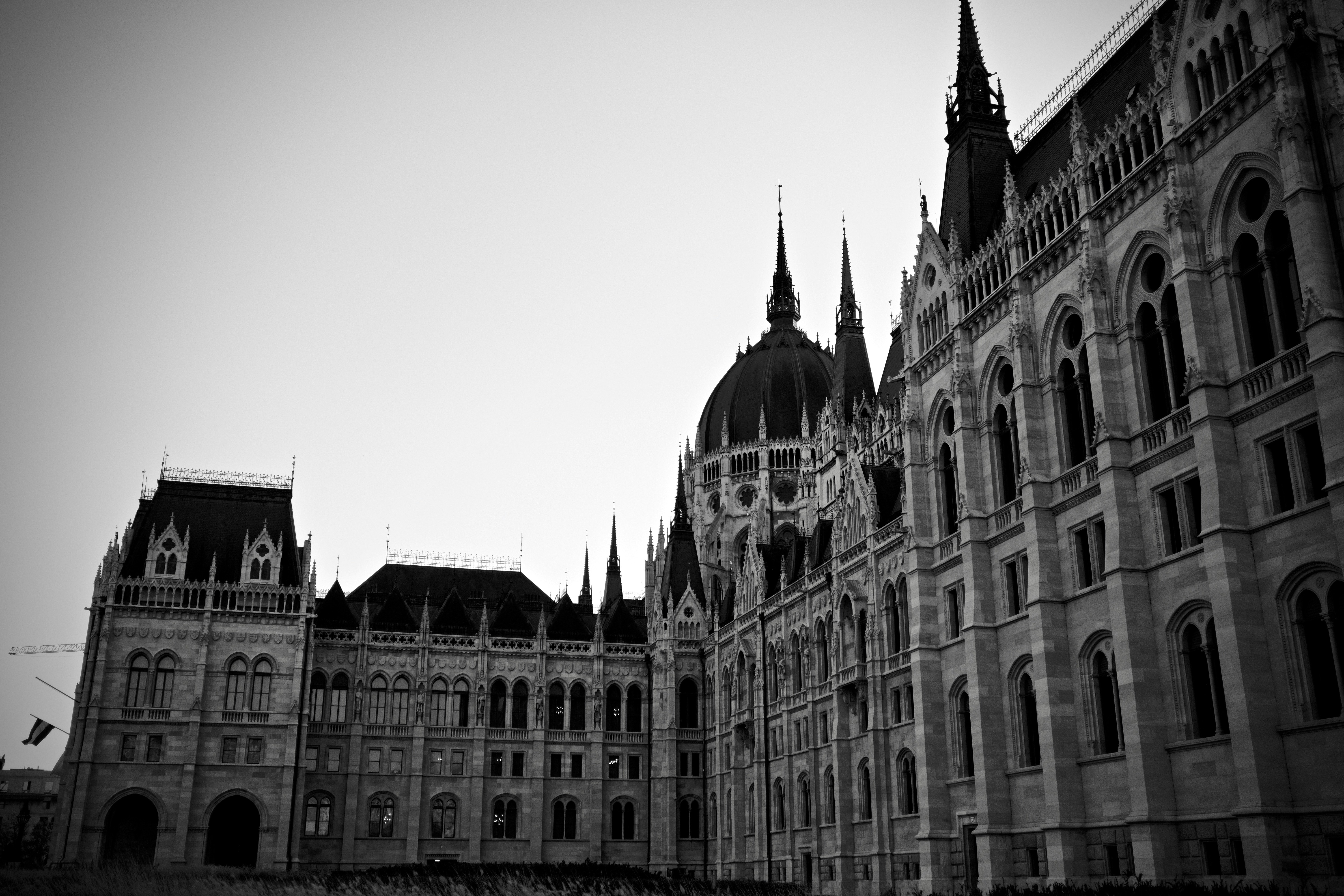 Black-and-white view of the Hungarian Parliament Building showcasing its neo-Gothic architecture under a cloudy sky.