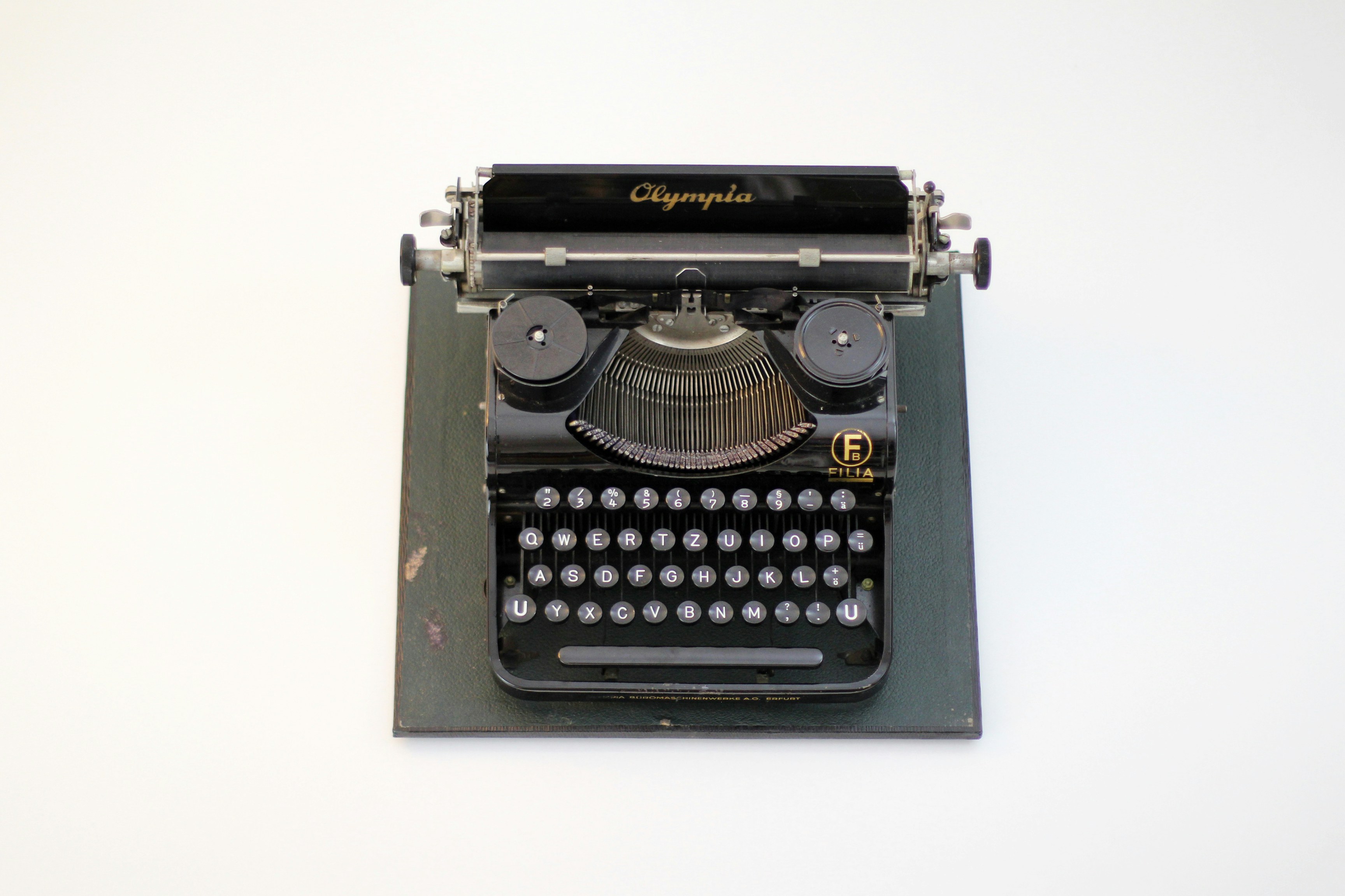 Vintage Olympia typewriter resting on a textured surface, showcasing its intricate keys and polished design.