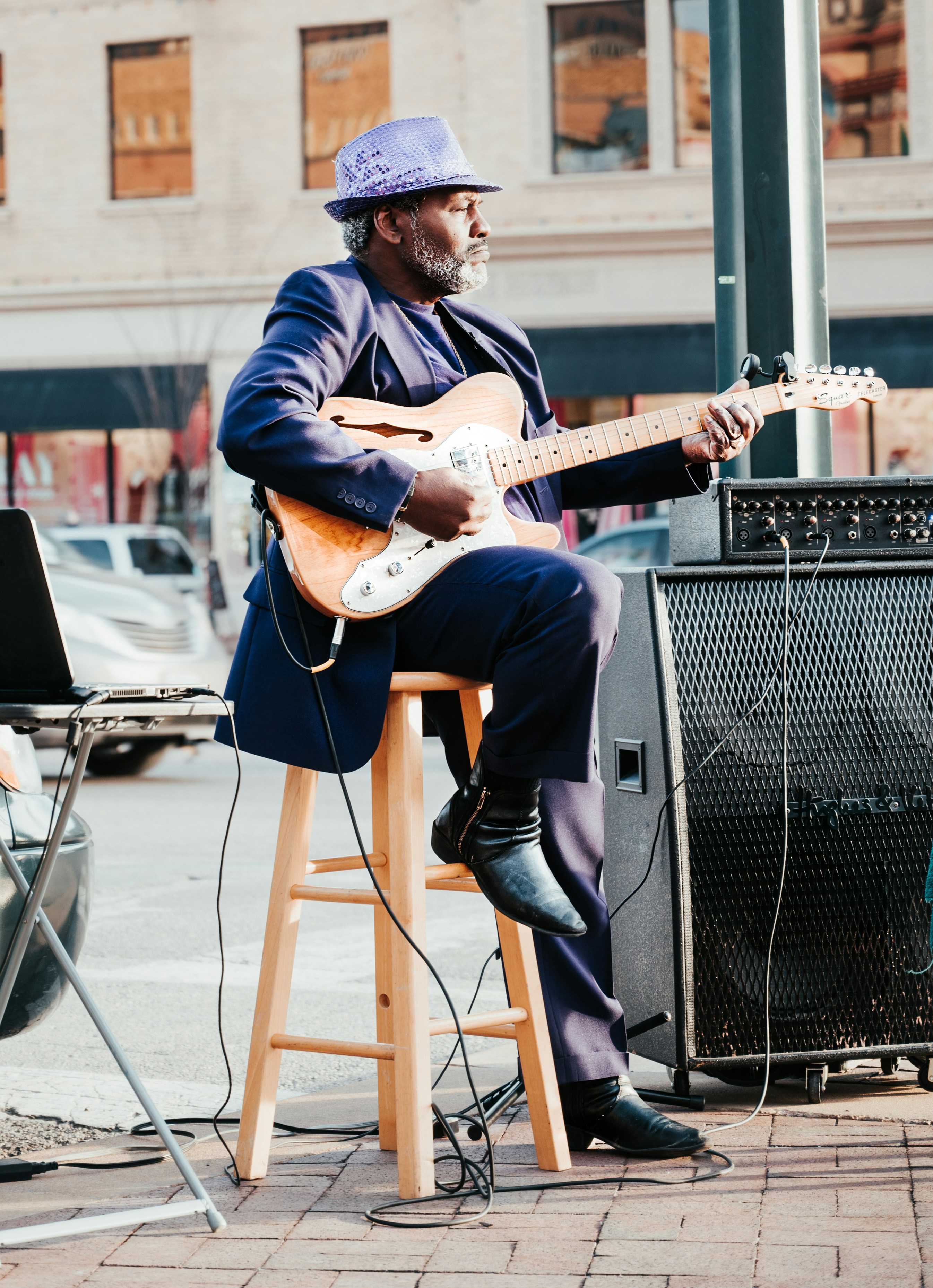 Urban Serenade on a Sunlit Street: A Guitarist in a Navy Suit