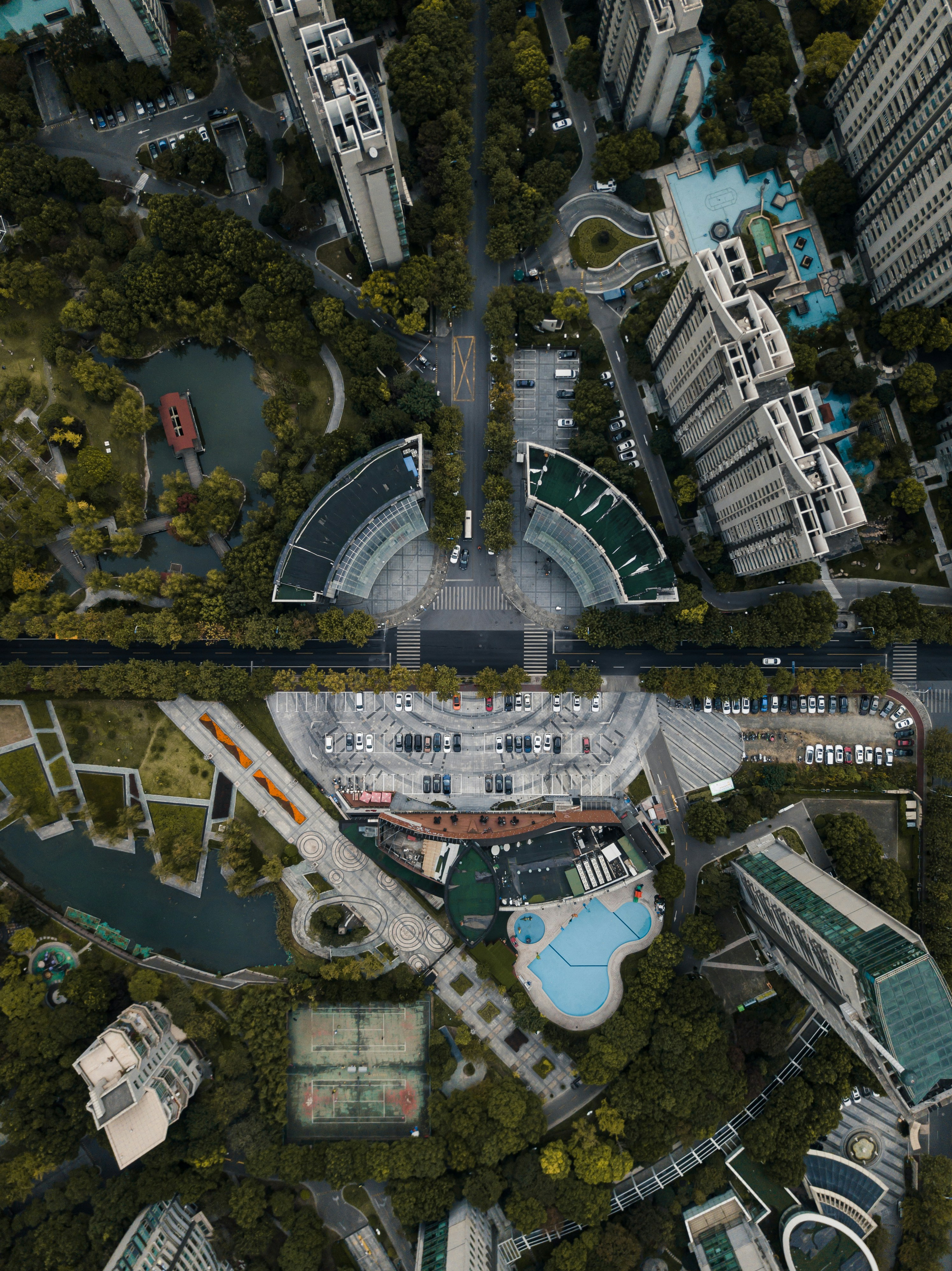 Aerial view of a modern urban landscape blending green spaces with architectural structures, showcasing a harmonious coexistence of nature and city life.