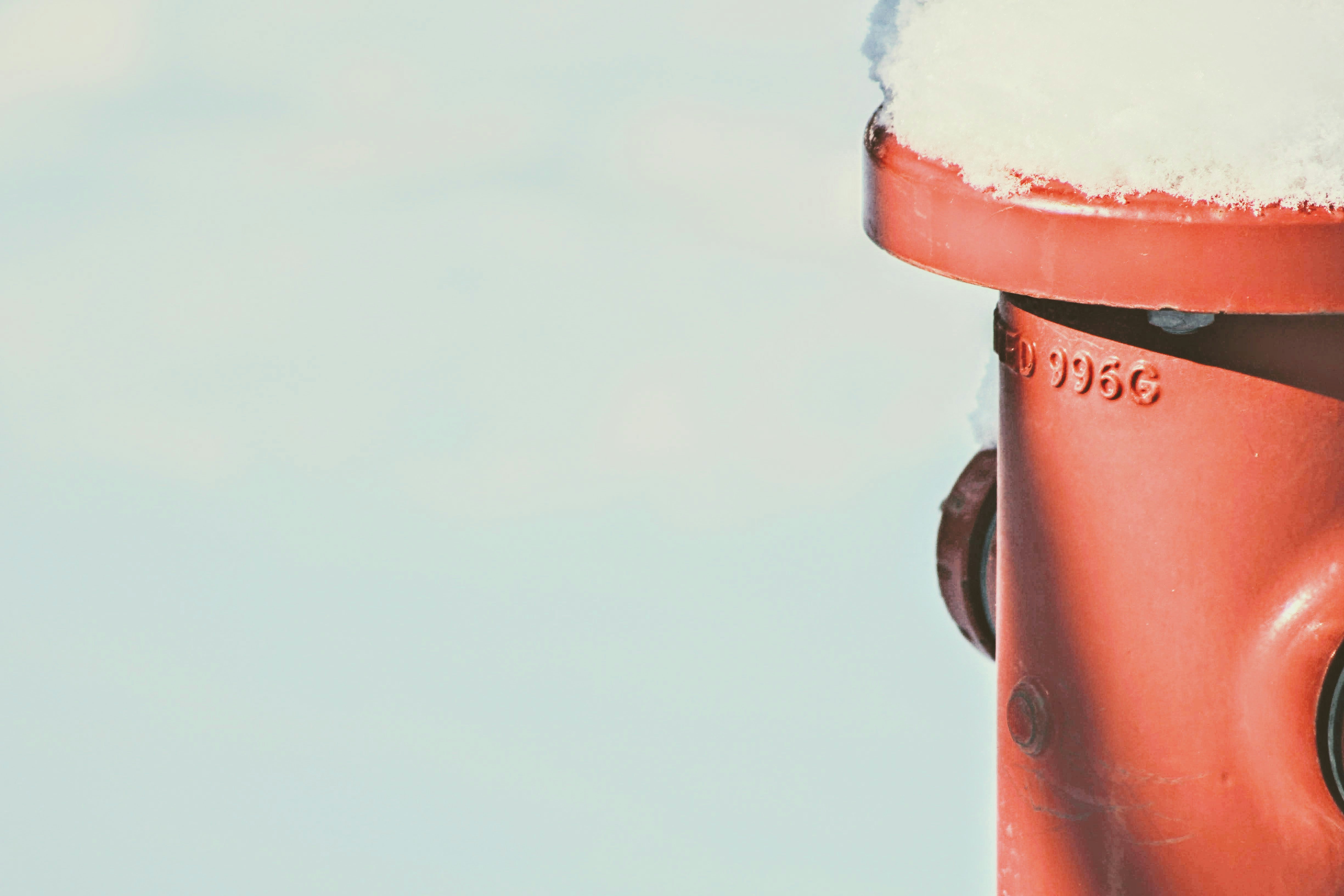 Snow-Capped Fire Hydrant Against a Pale Winter Sky