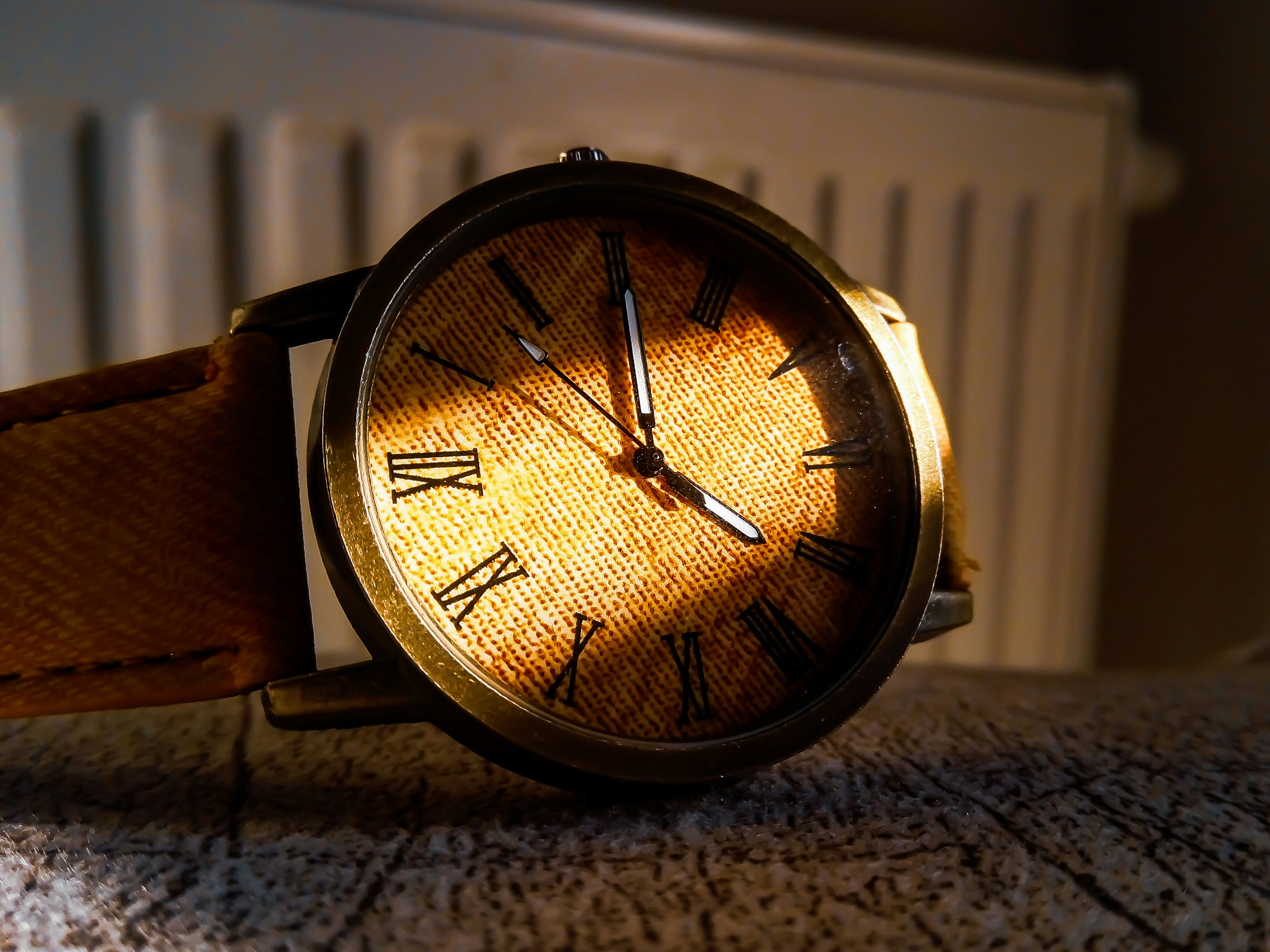 Patina Under Warm Glow: A Vintage Leather Watch on a Textured Surface