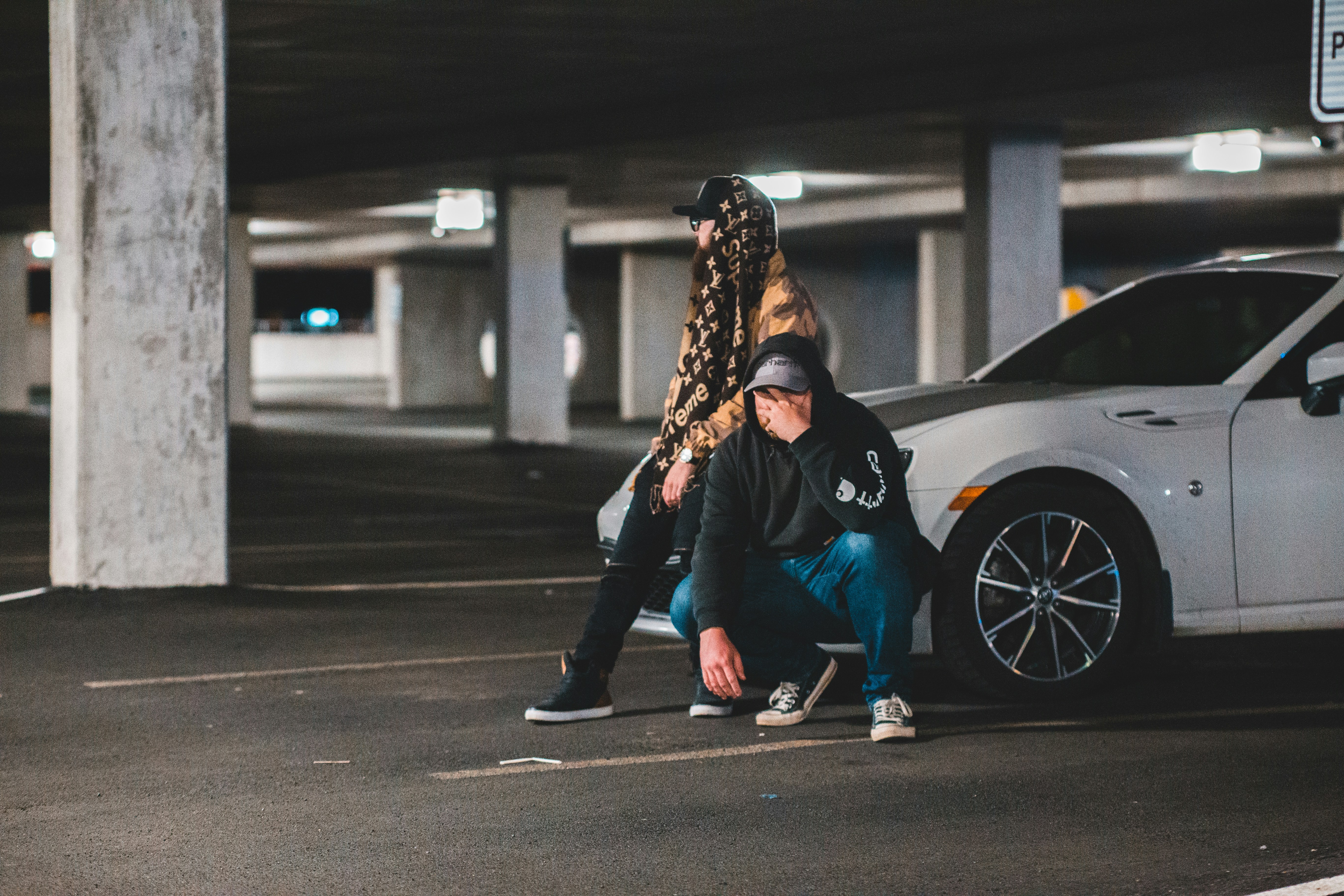 Man crouching beside man sitting on car's hood photo – Free Grey Image ...