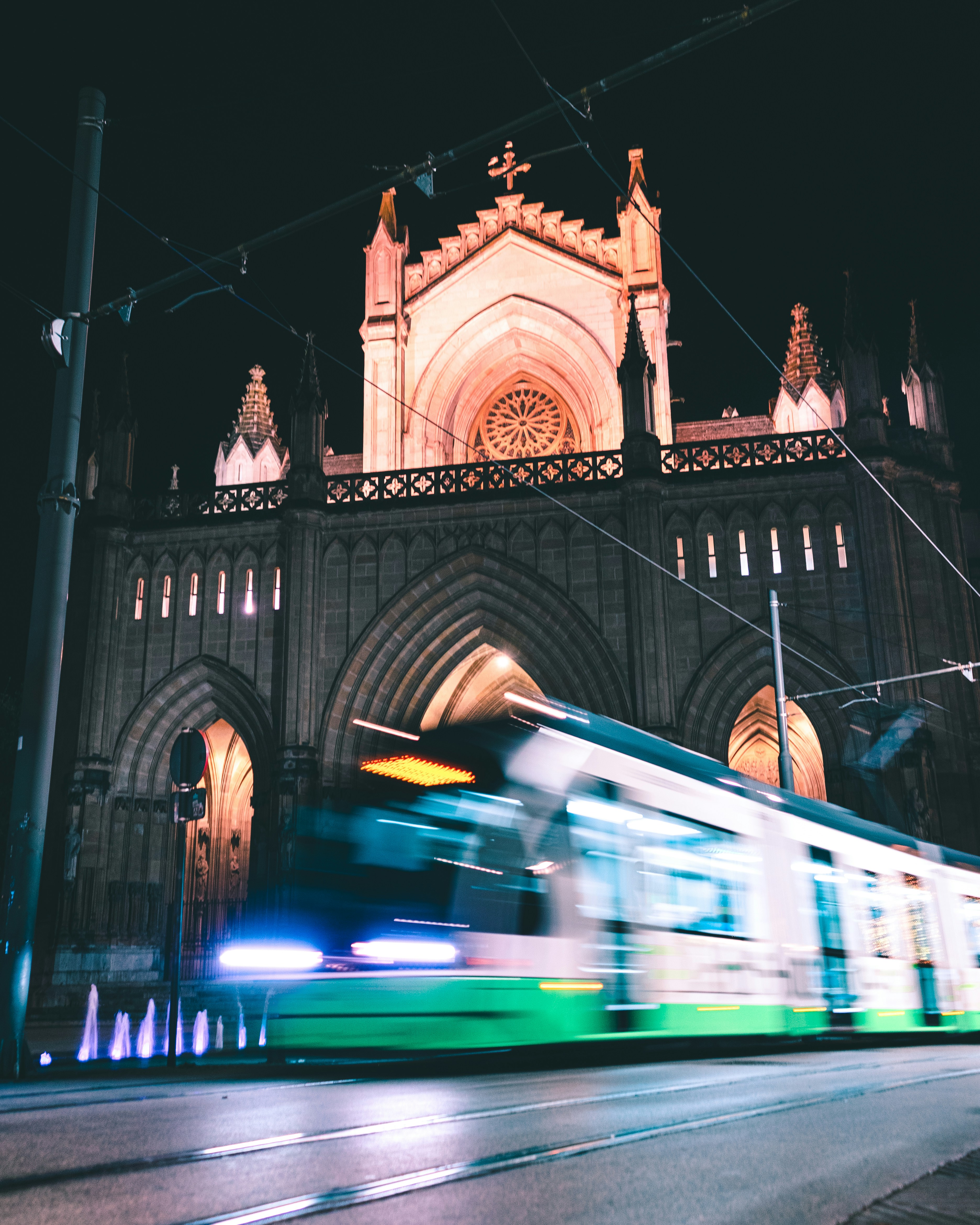 Gothic Facade in Transit: Night Tram Crossing the Cathedral Way