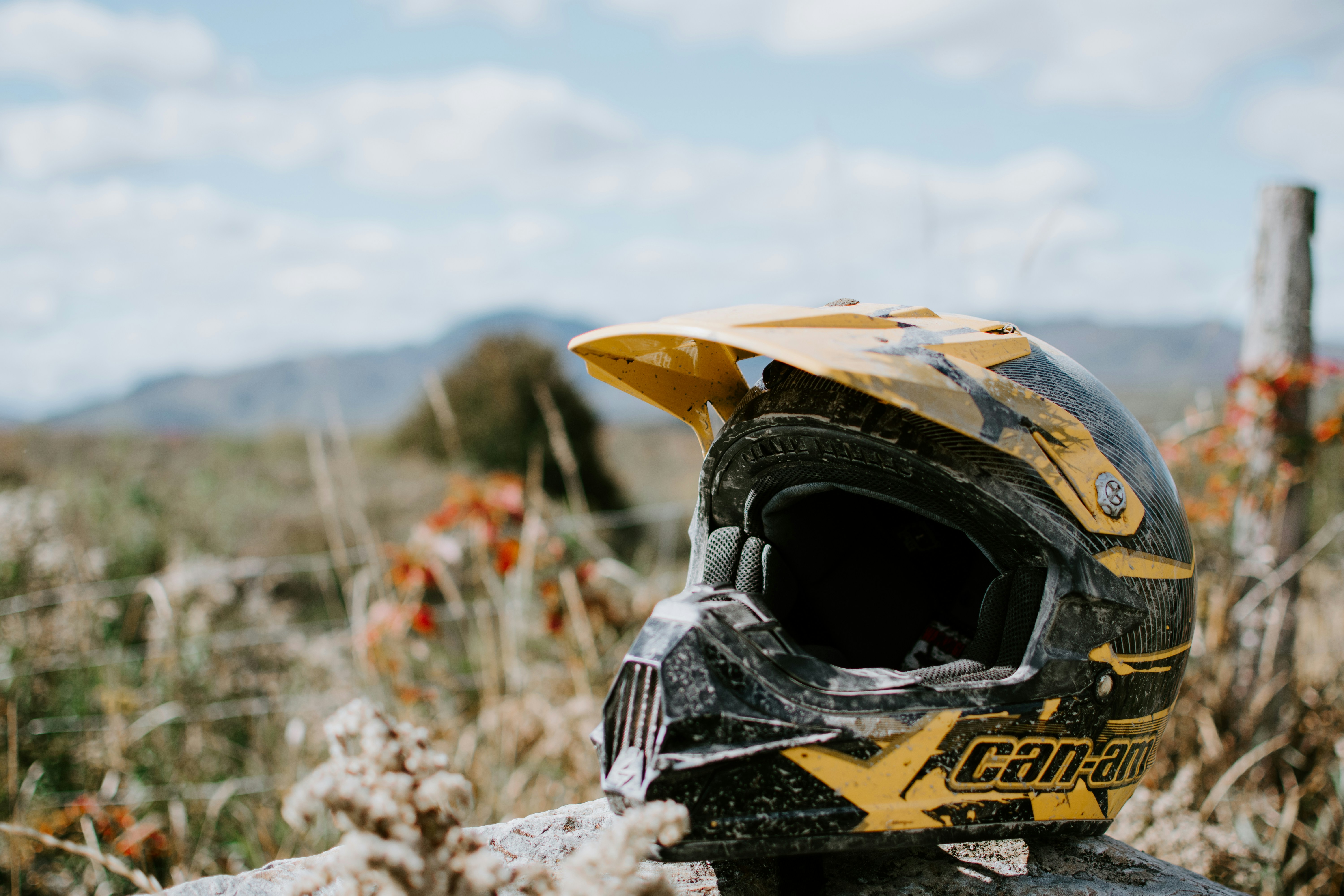 Sunlit Field Moment: A Yellow Motocross Helmet Resting on Weathered Stone