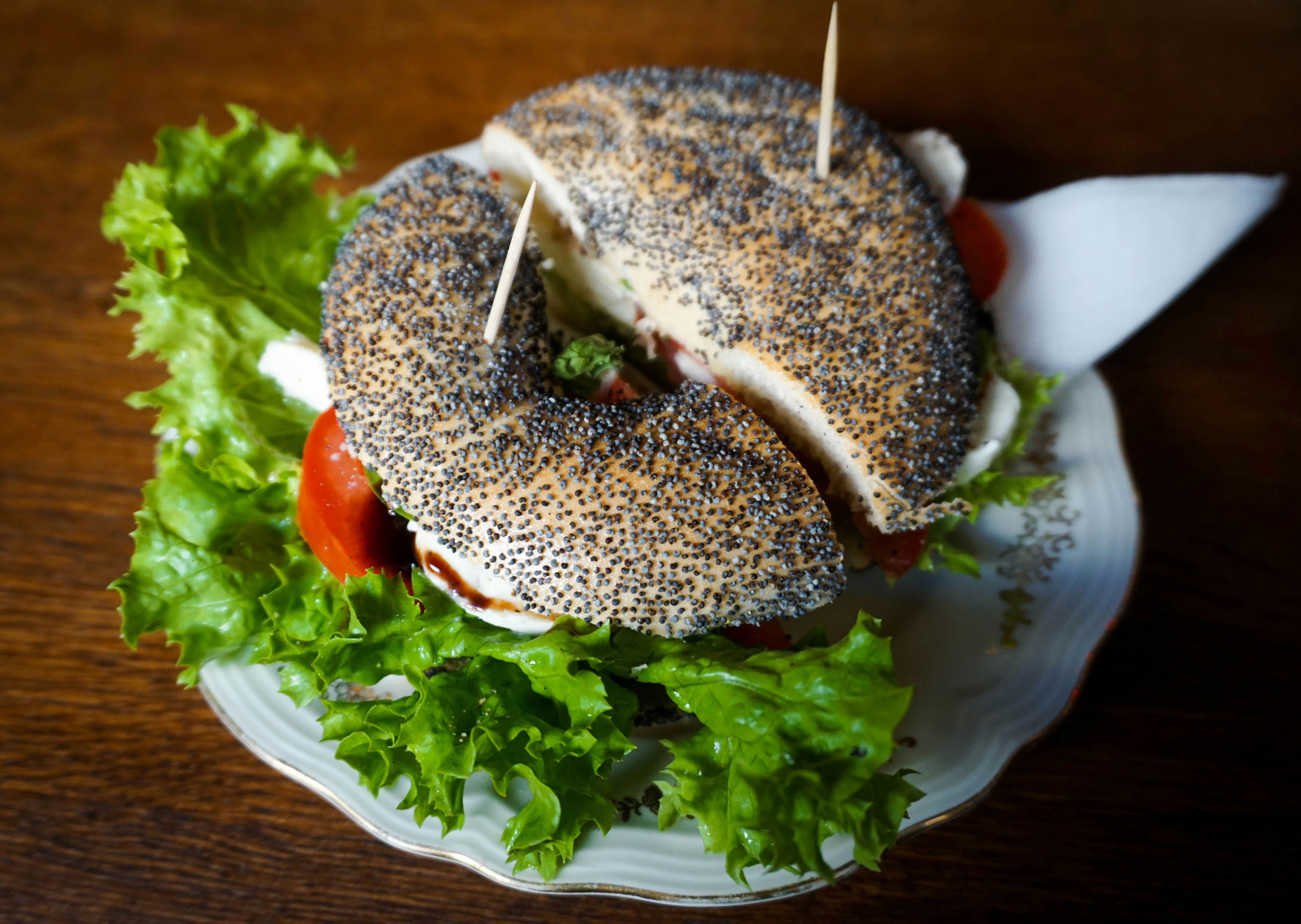 Sesame-Bagel Sandwich Nestled with Greens on a Rustic Plate