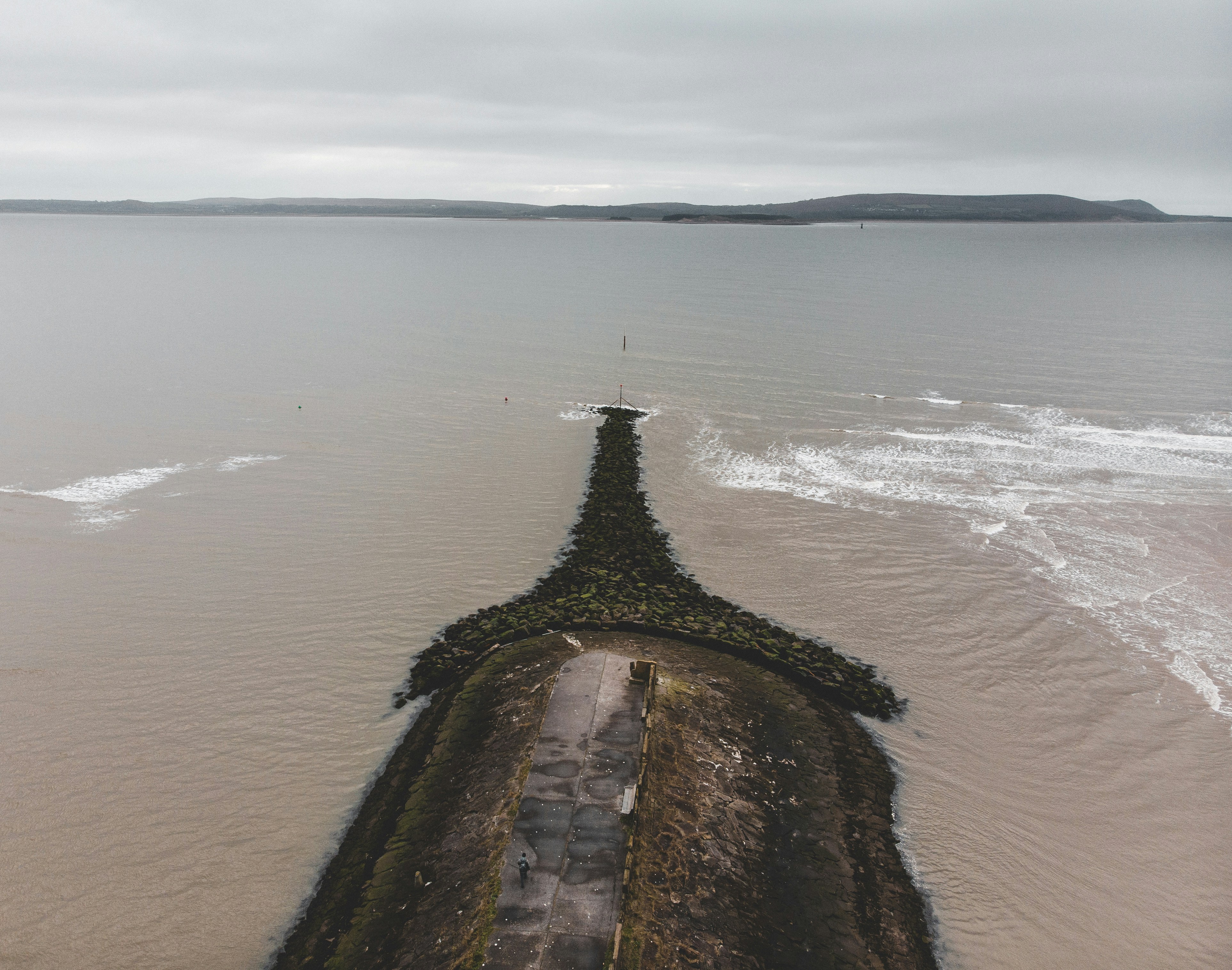 End of the Causeway: Aerial portrait of a tidal jetty piercing a calm sea