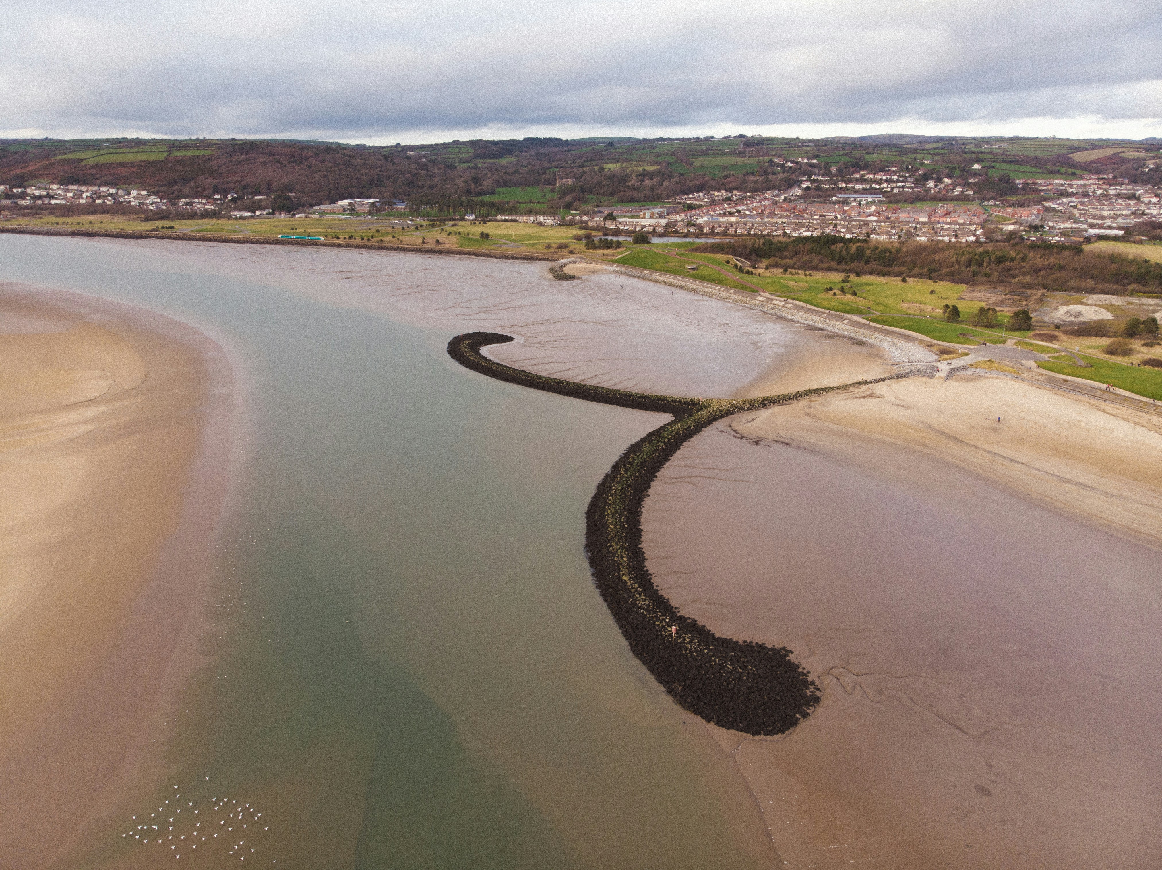 Arc of Stone: A Seaward Jetty Carves a Quiet Inlet Against a Coastal Town