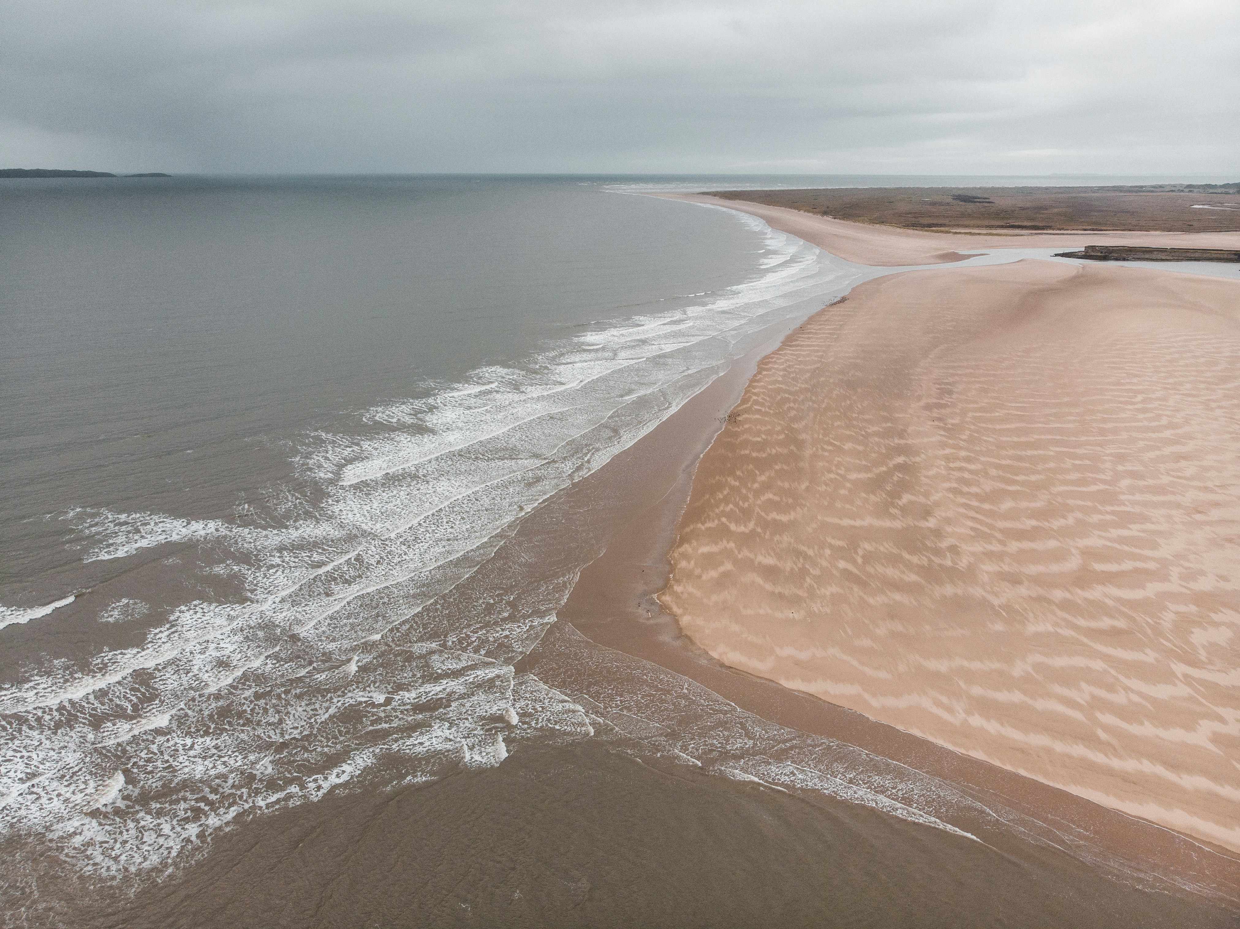 Gentle waves lapping at a sandy shore under a moody sky, showcasing the harmony of land and water.