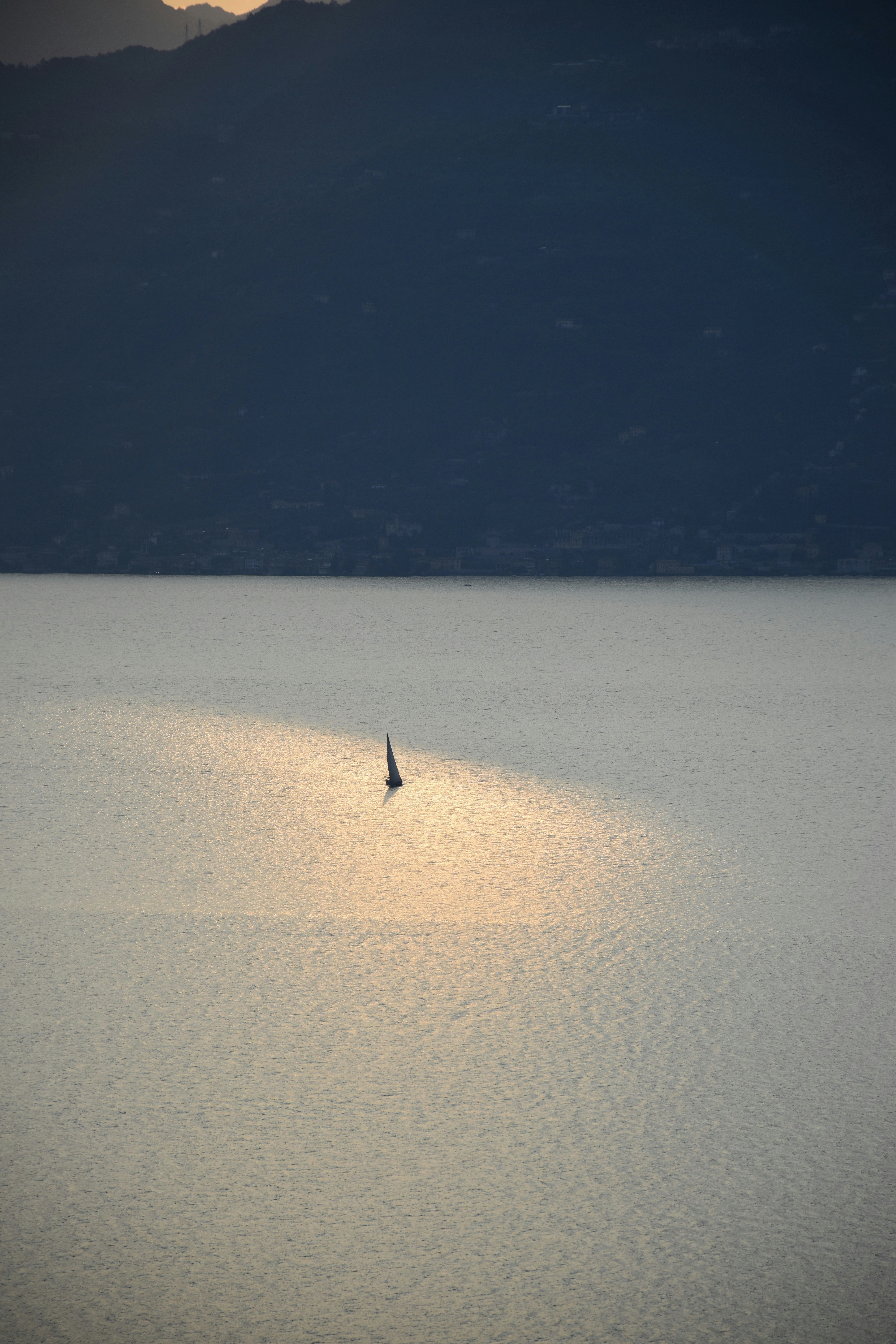 Dawn's Silver Wake: A Lone Sailboat on a Glassy Fjord