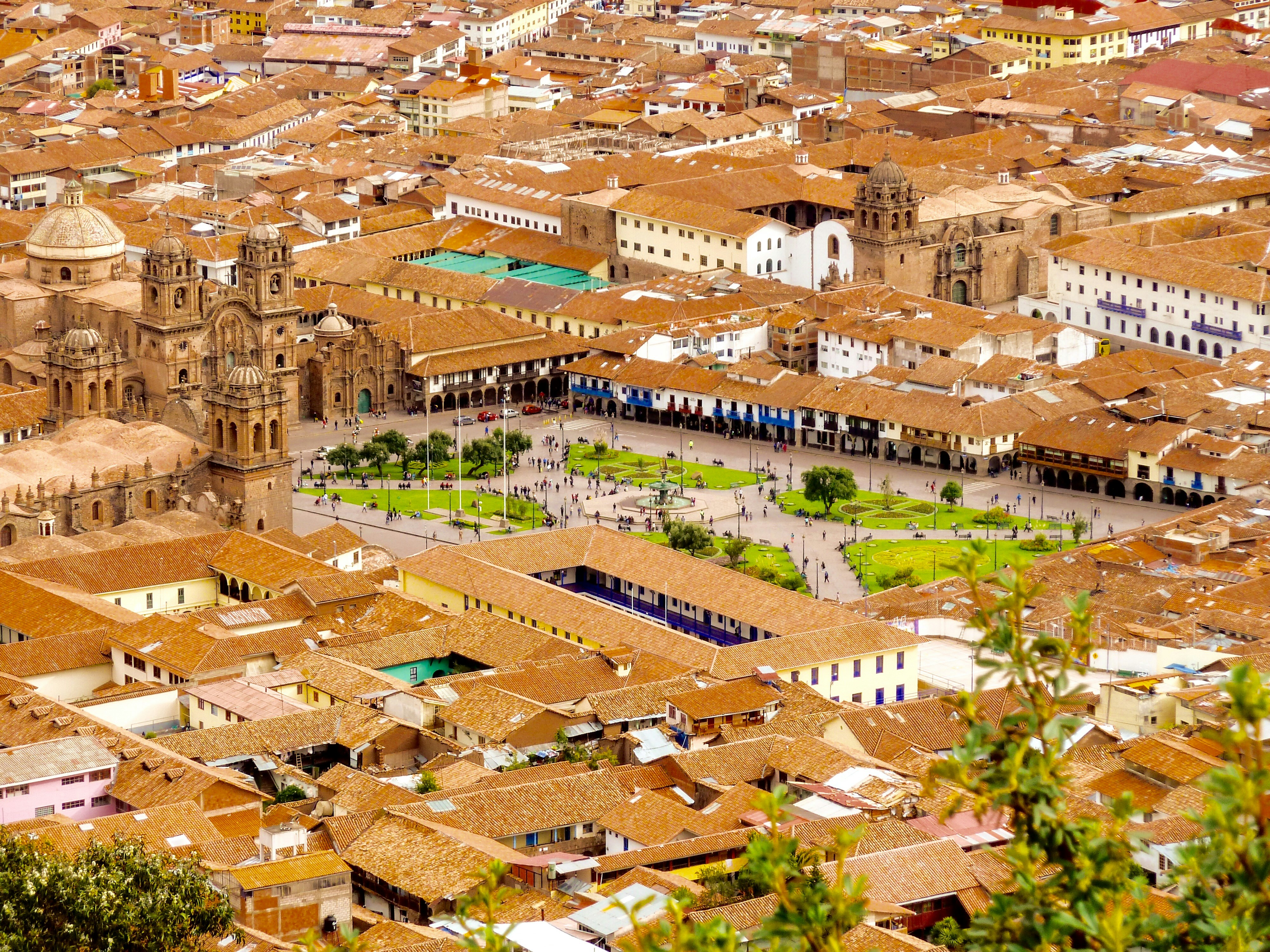 Aerial view of Cusco's Plaza de Armas with terracotta rooftops and historic architecture.