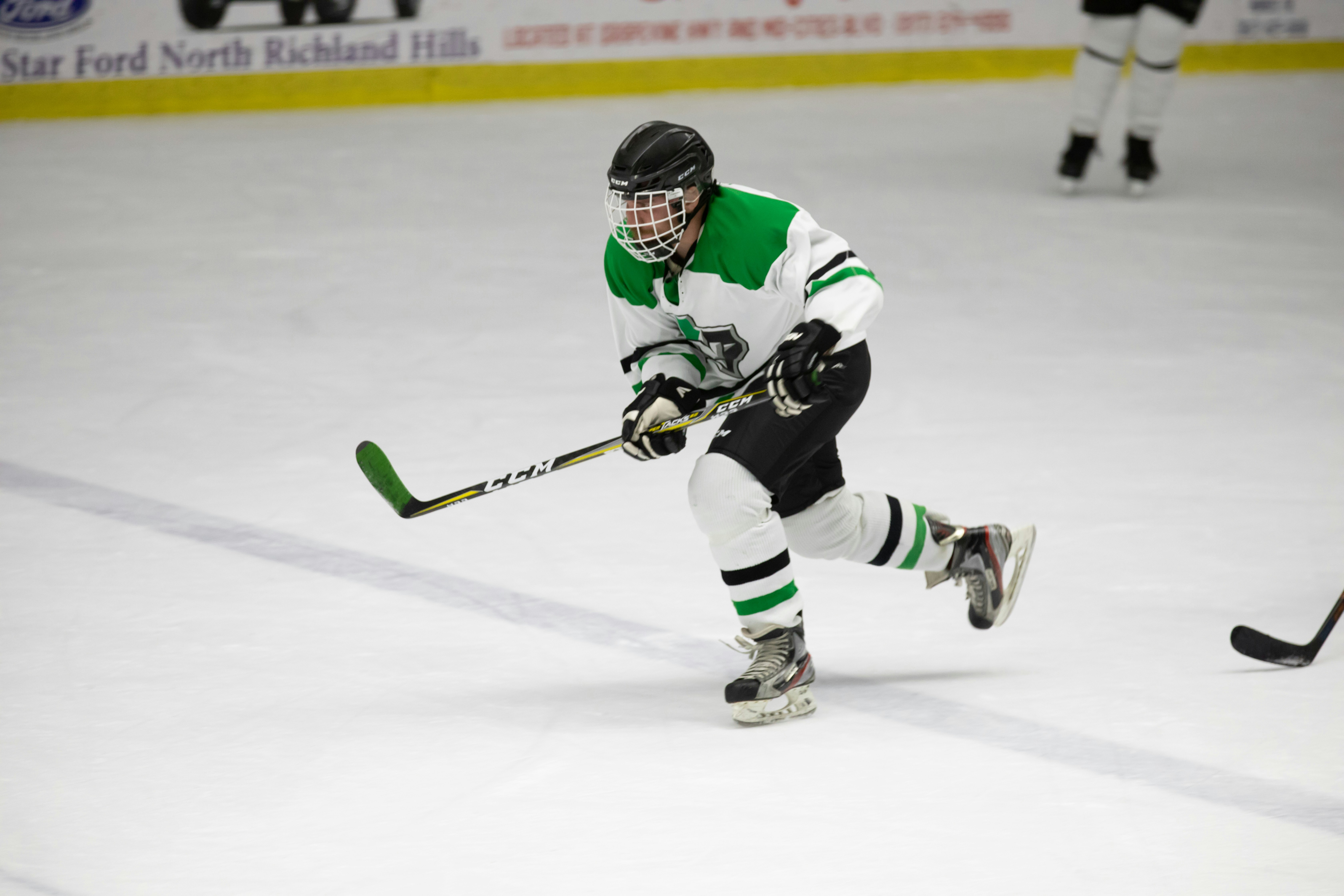 Hockey player sprinting down the ice. | men playing ice hockey game