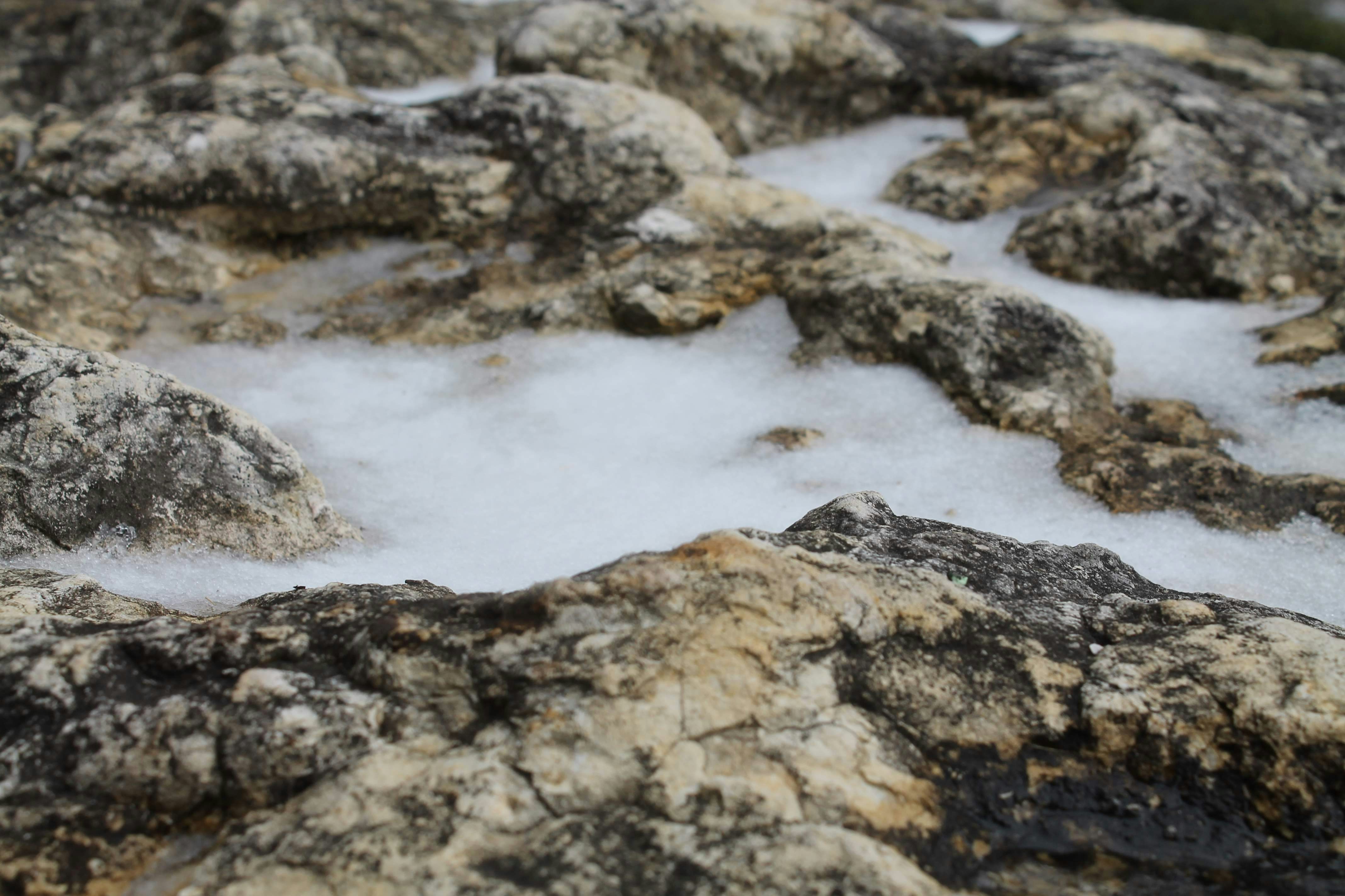 Crusty rock formations partially covered with thin layers of snow.