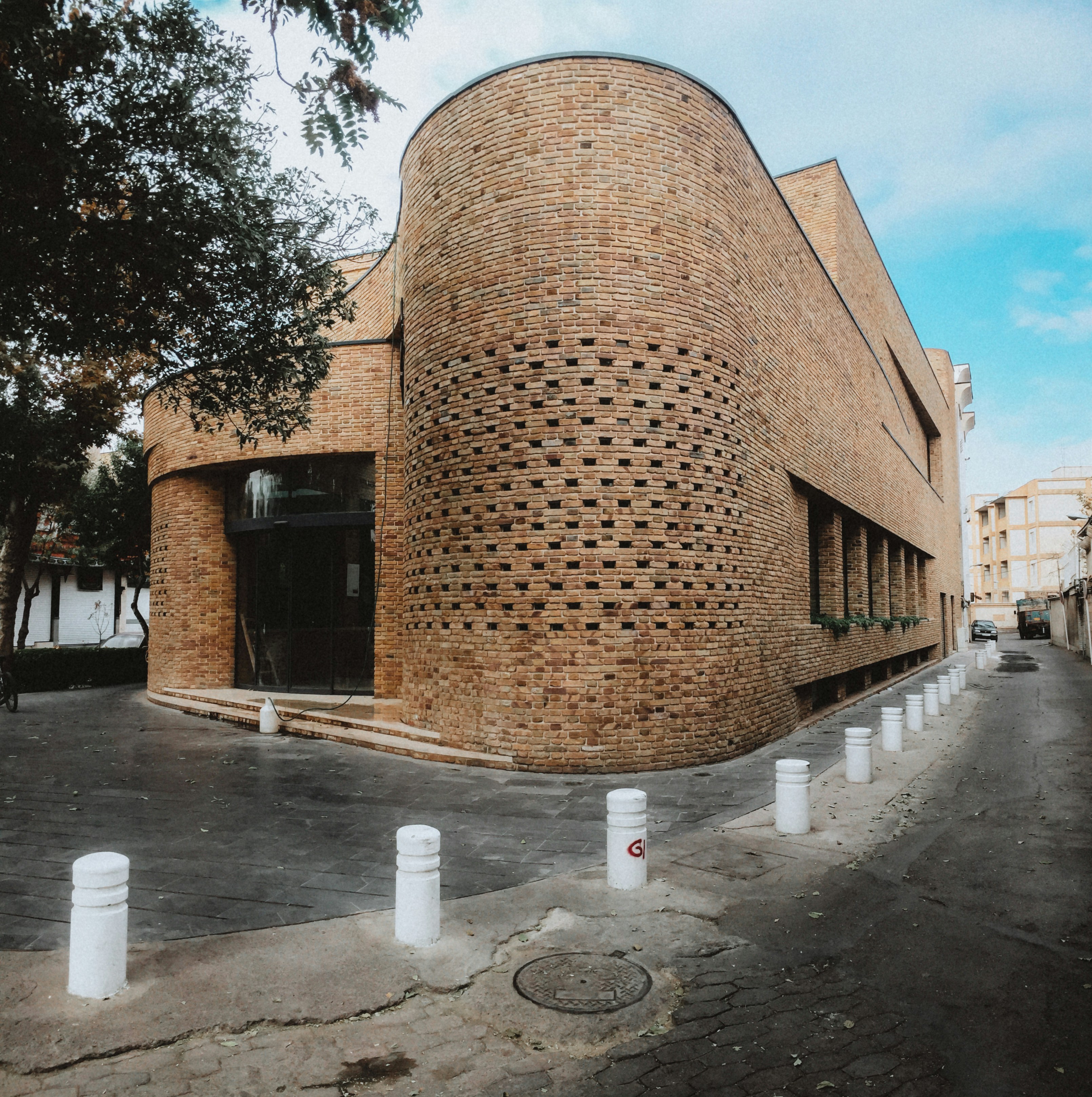 The Circular Brick Corner: Perforated Facade Framing a Quiet Street