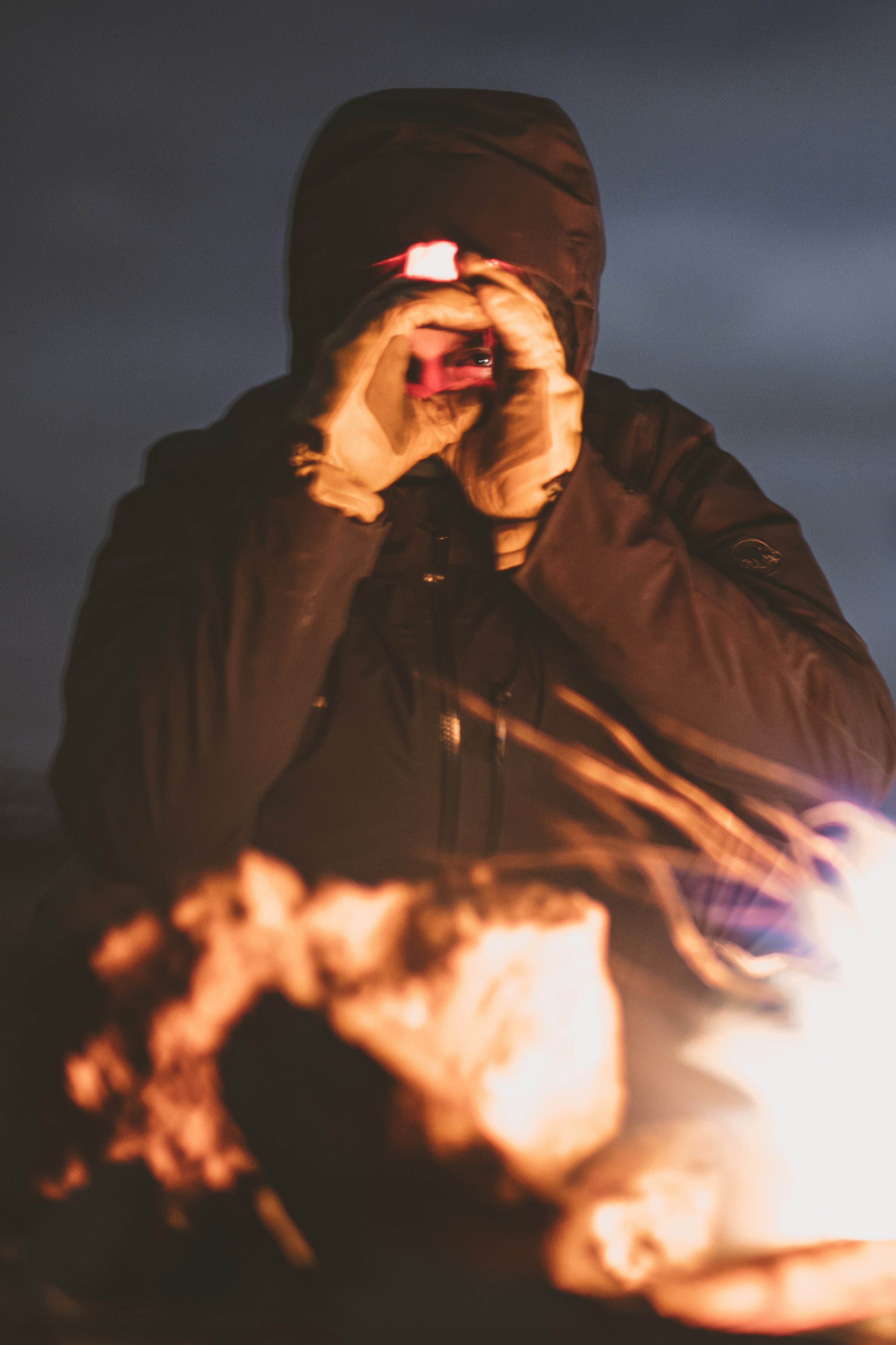 Emberframe: A Hooded Silhouette Framed by Firelight