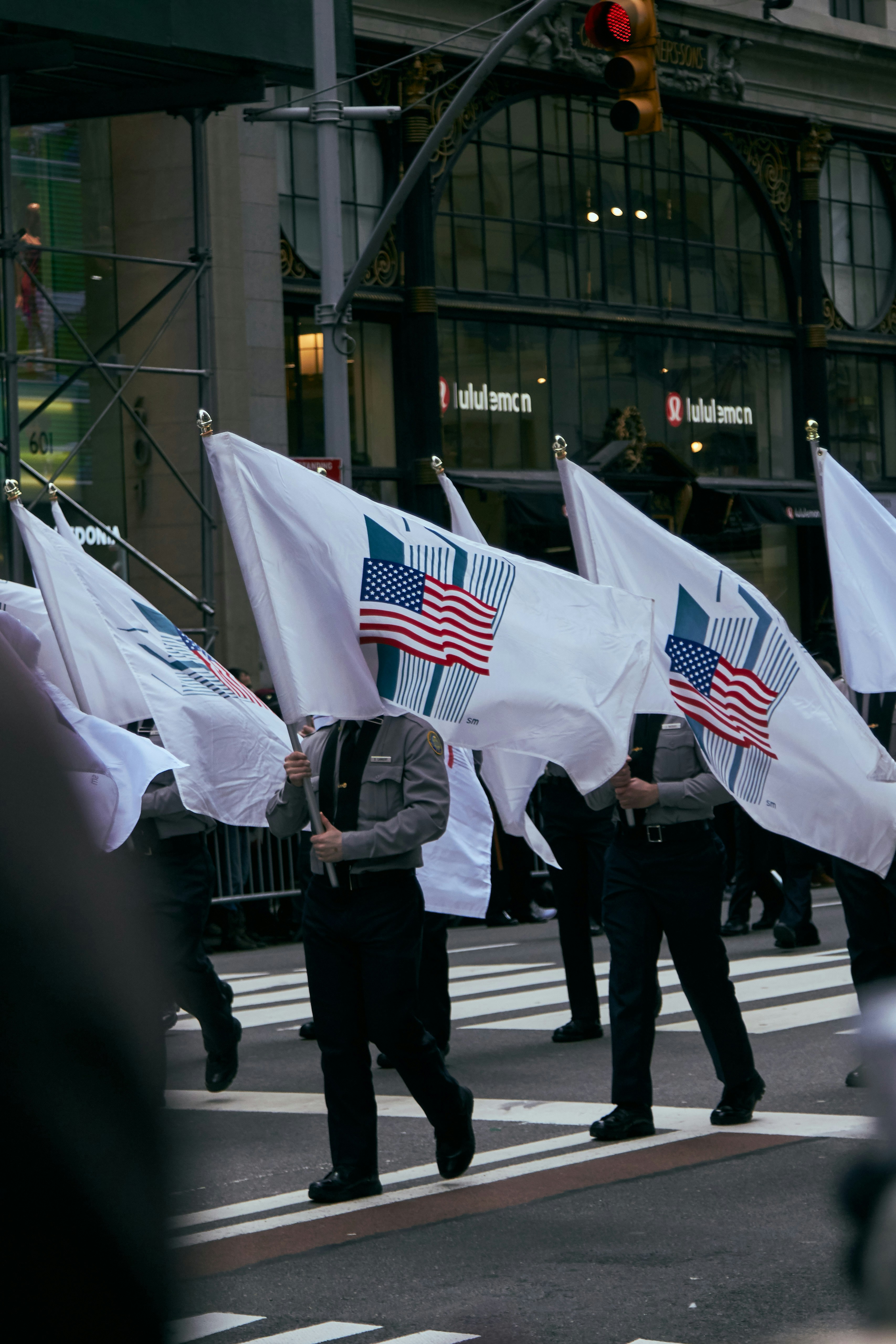 Rhythms of the Crosswalk: Flagbearers March Under Glass Facades