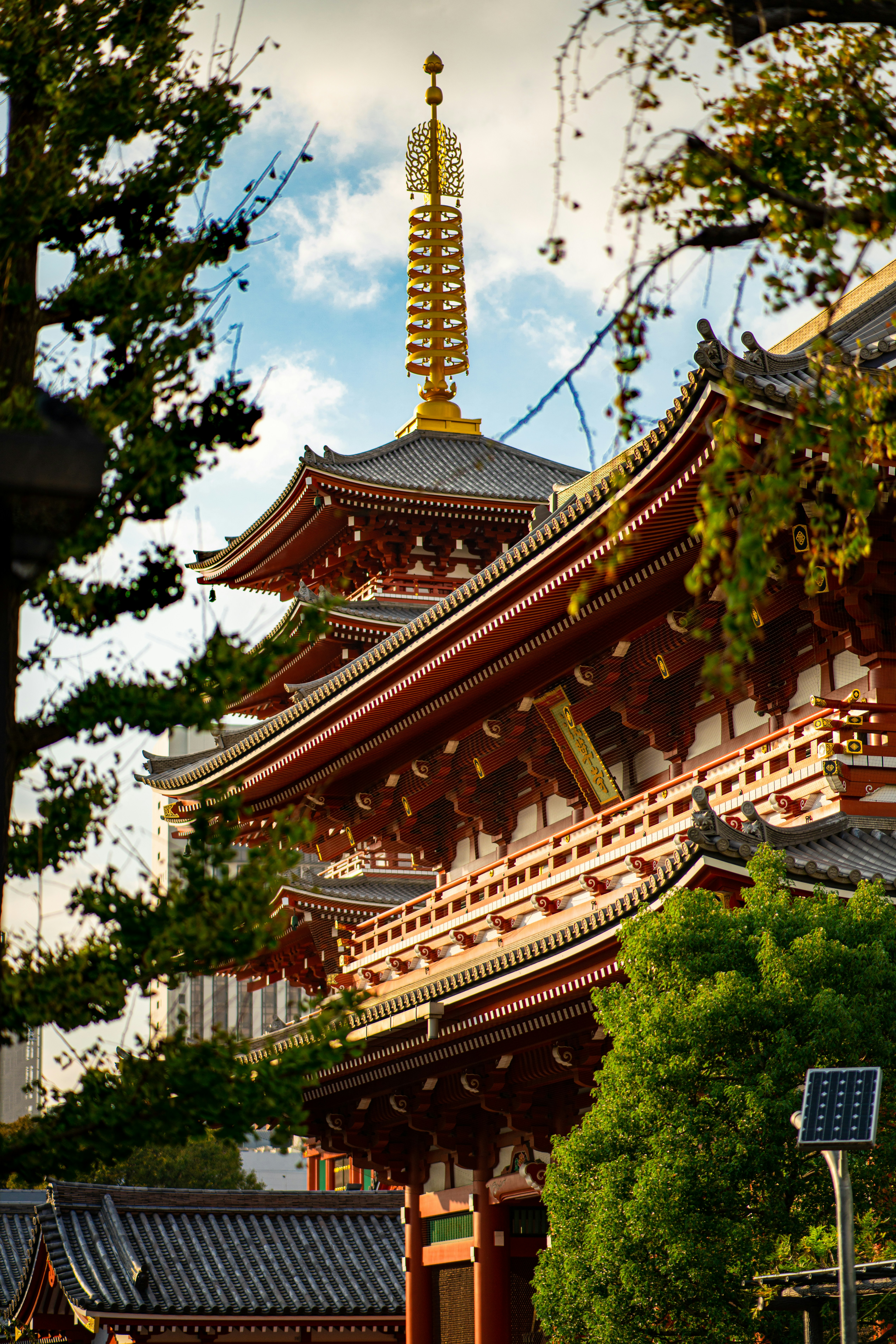 Intricate details of a traditional Japanese temple showcase ornate roofs and a towering pagoda, framed by lush greenery.
