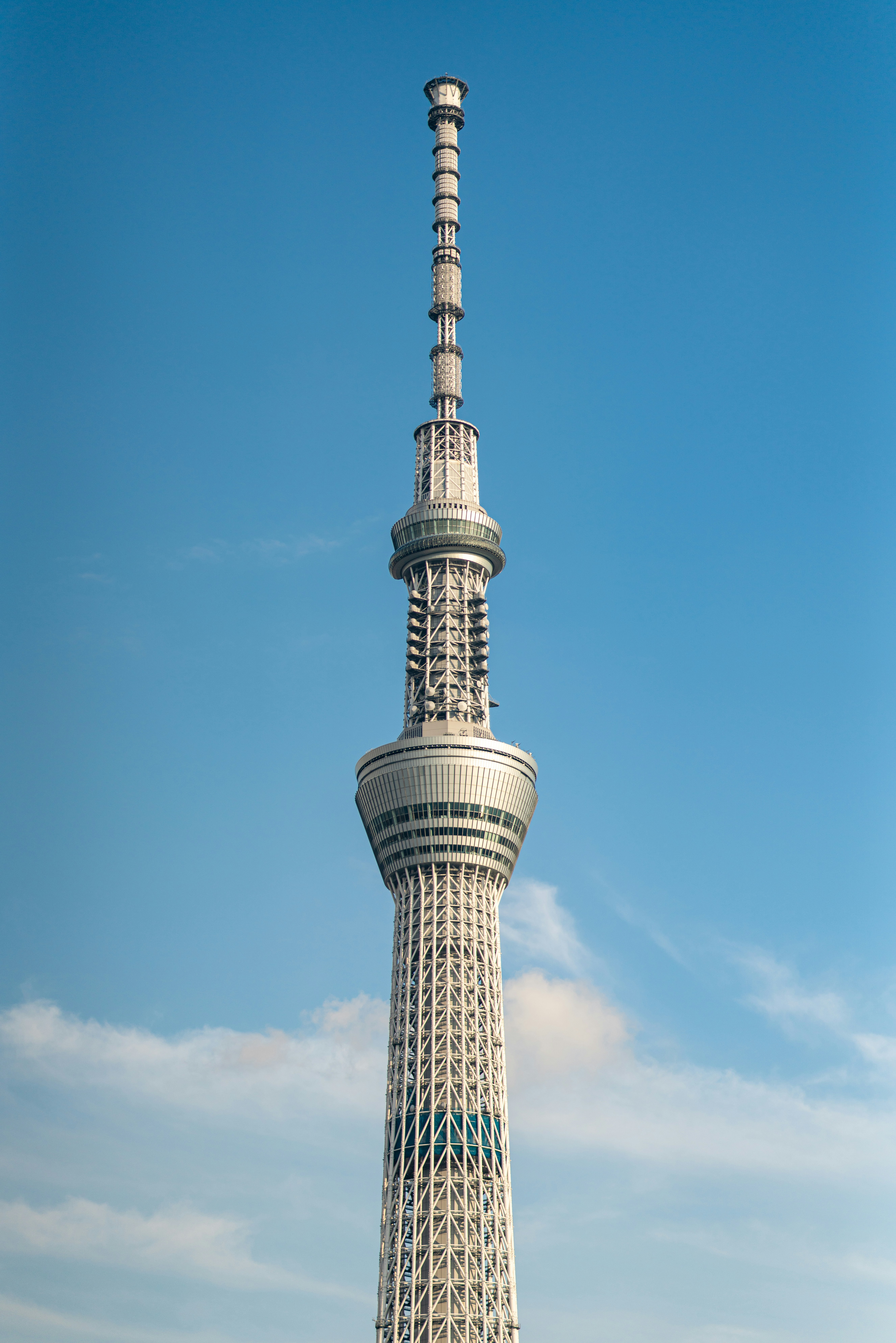 Tokyo Skytree rises majestically against a clear blue sky, showcasing its intricate design and towering presence.