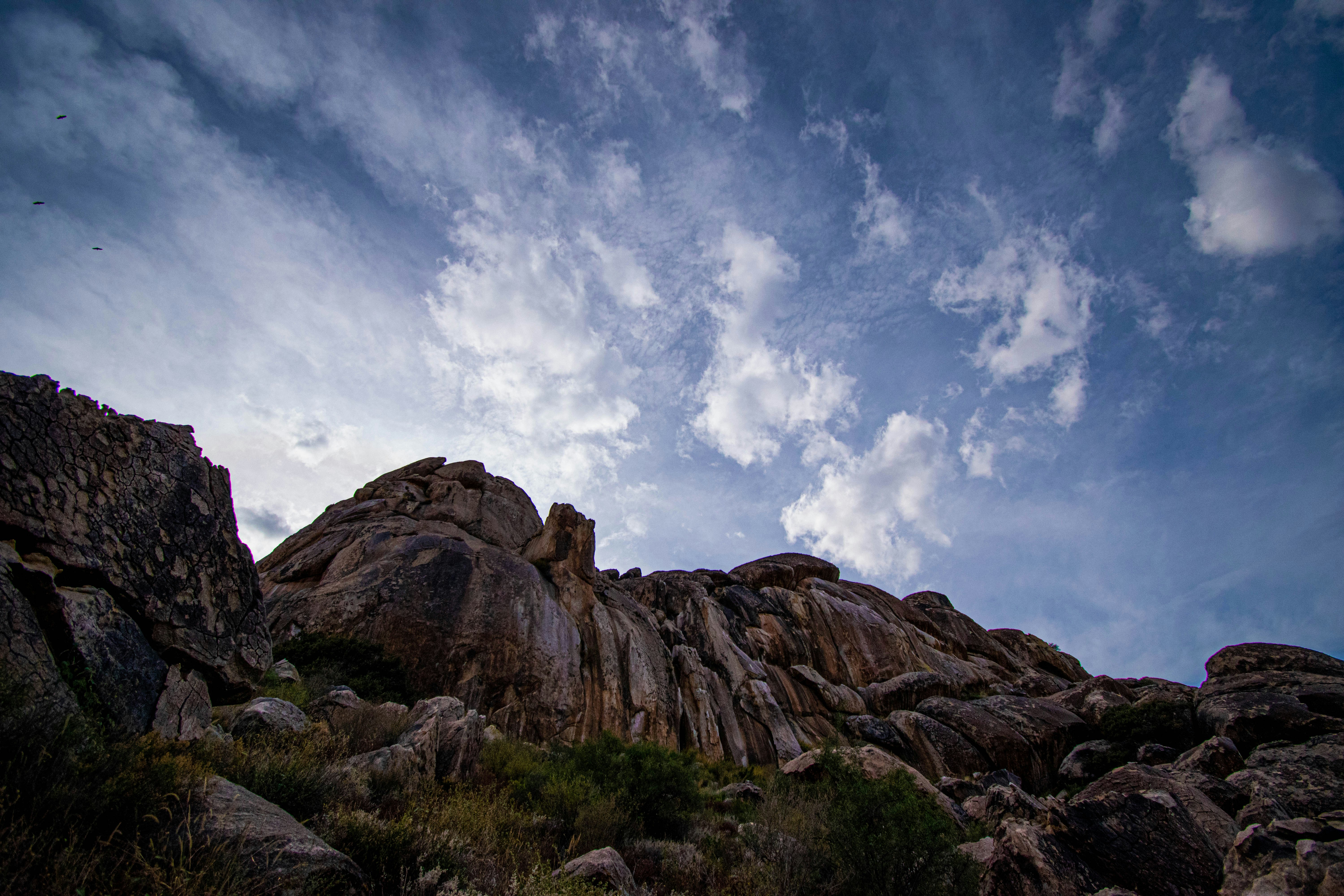 Low angle view of rocky mountain peaks beneath a dynamic cloudy sky.