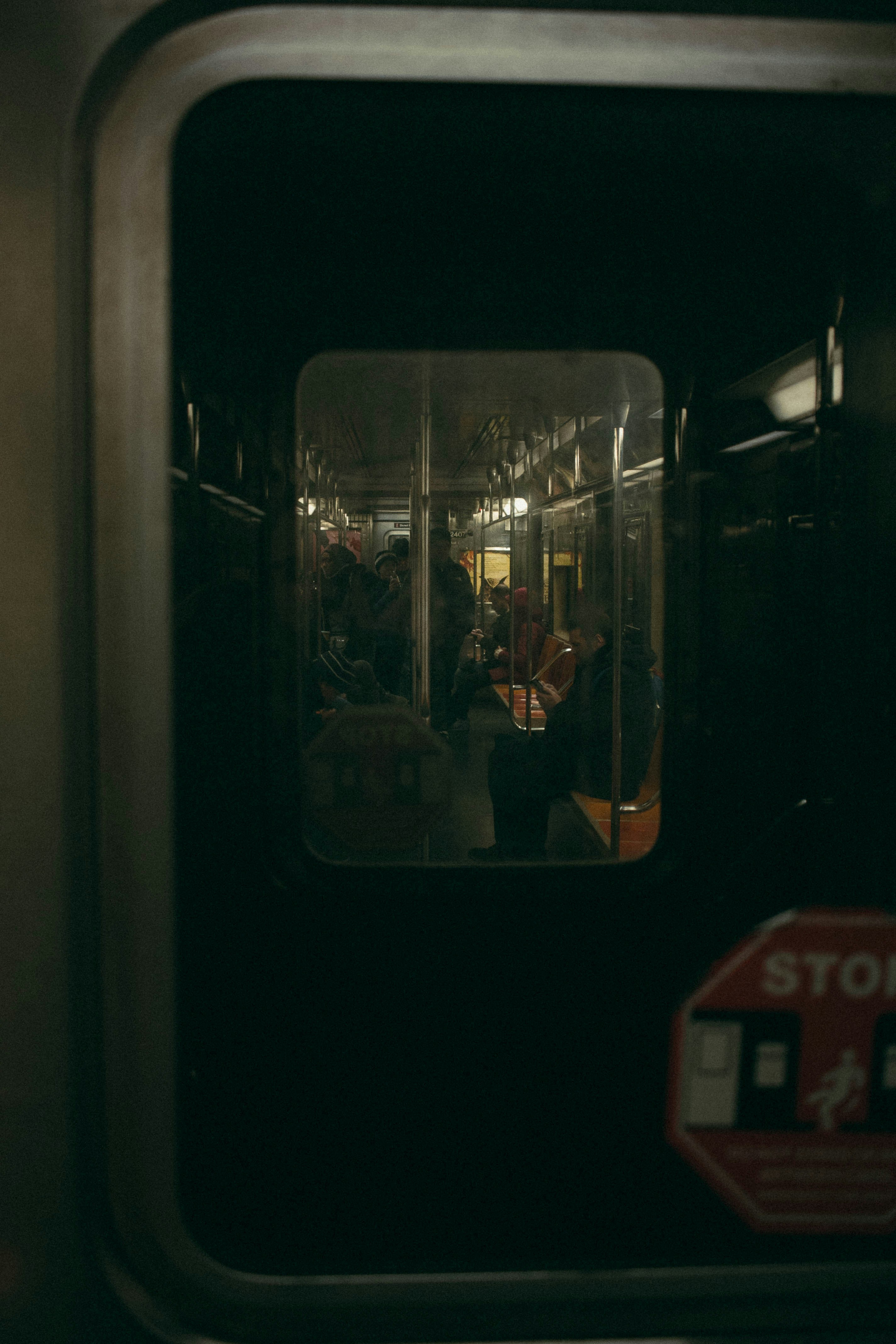 View through a subway door revealing passengers immersed in their journeys. The scene captures the essence of urban commuting.