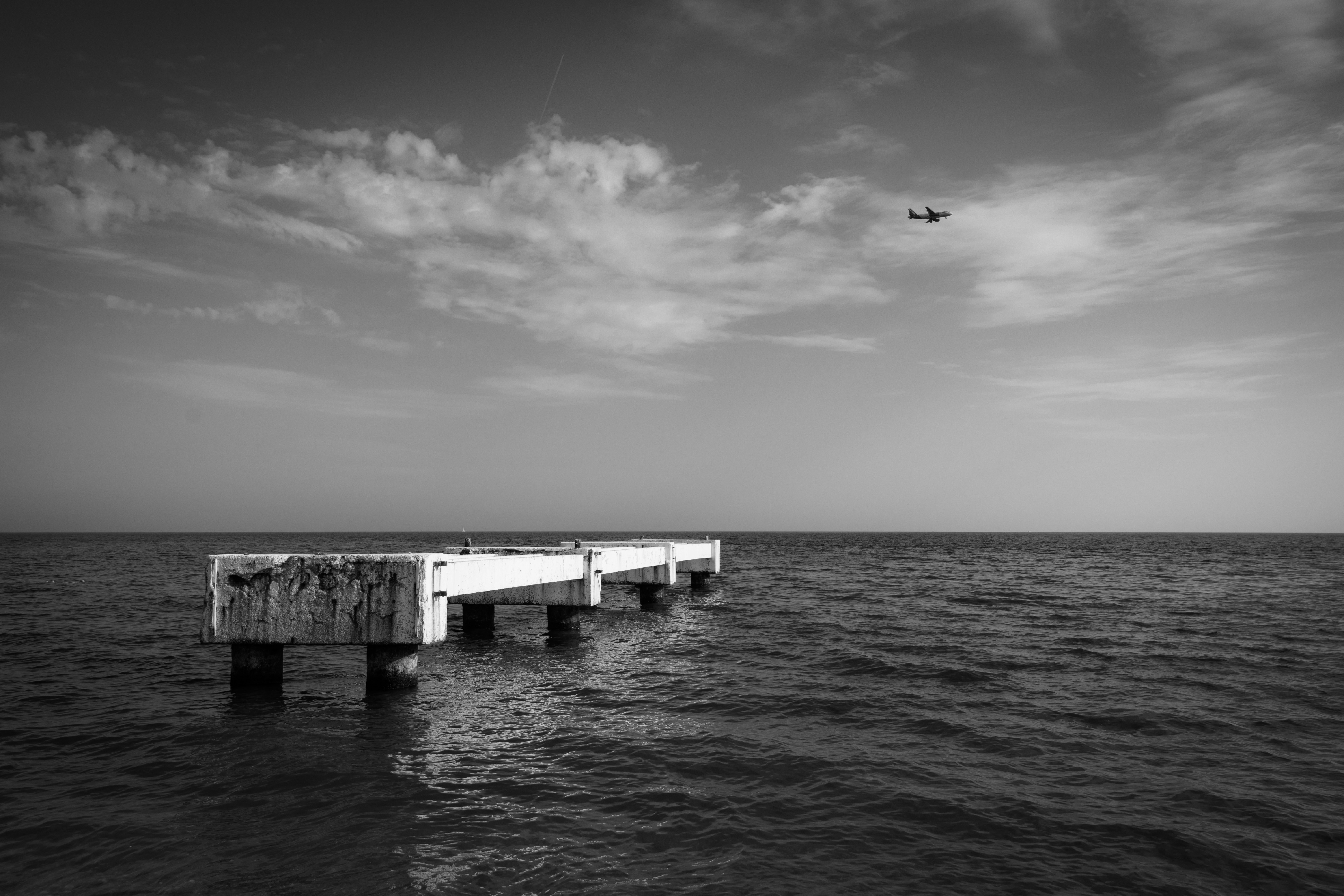 Deserted pier stretches into the quiet sea under a drifting sky