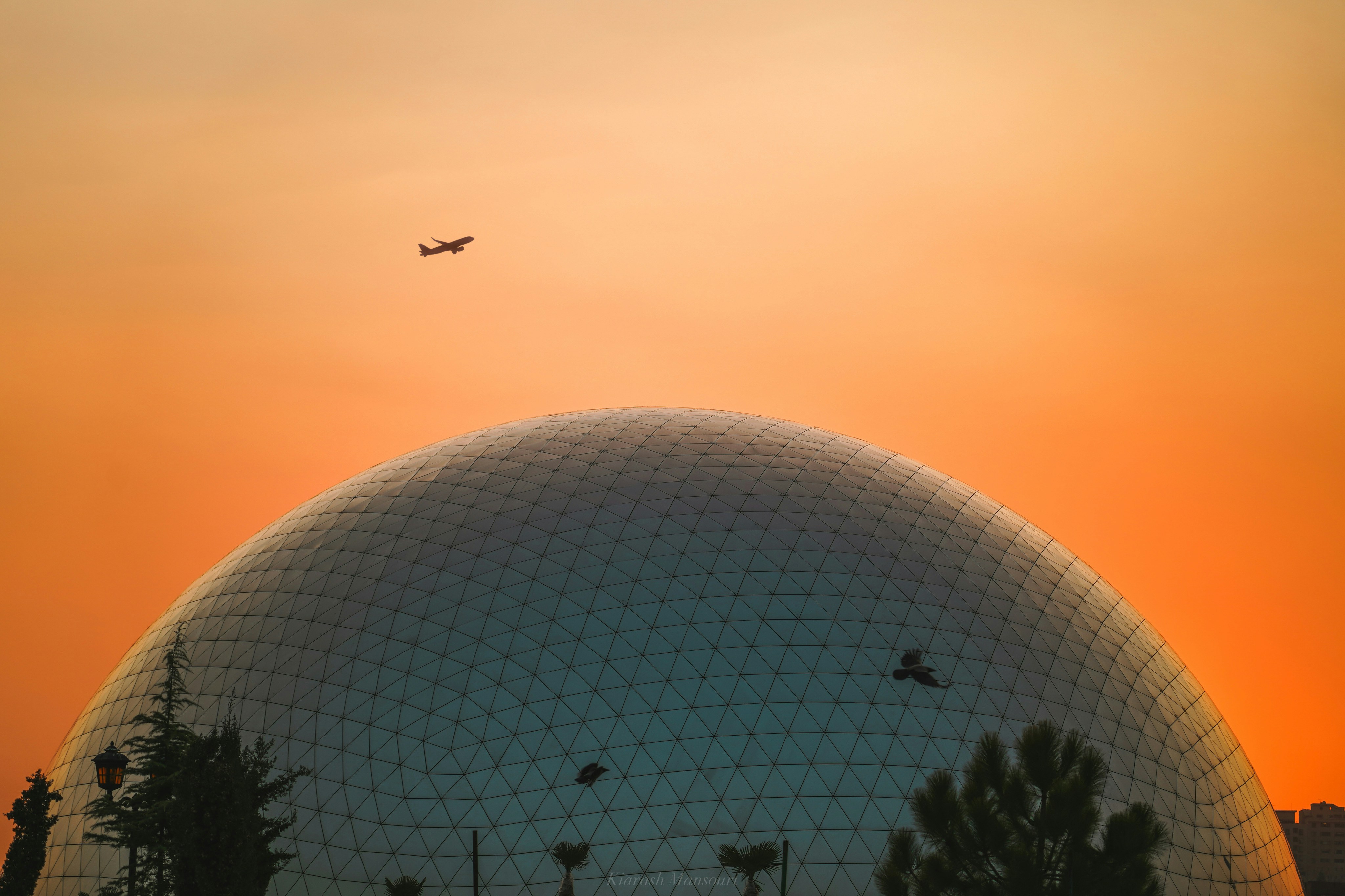 Ember Sky Over a Geodesic Dome: Dusk Silhouettes and a Passing Plane