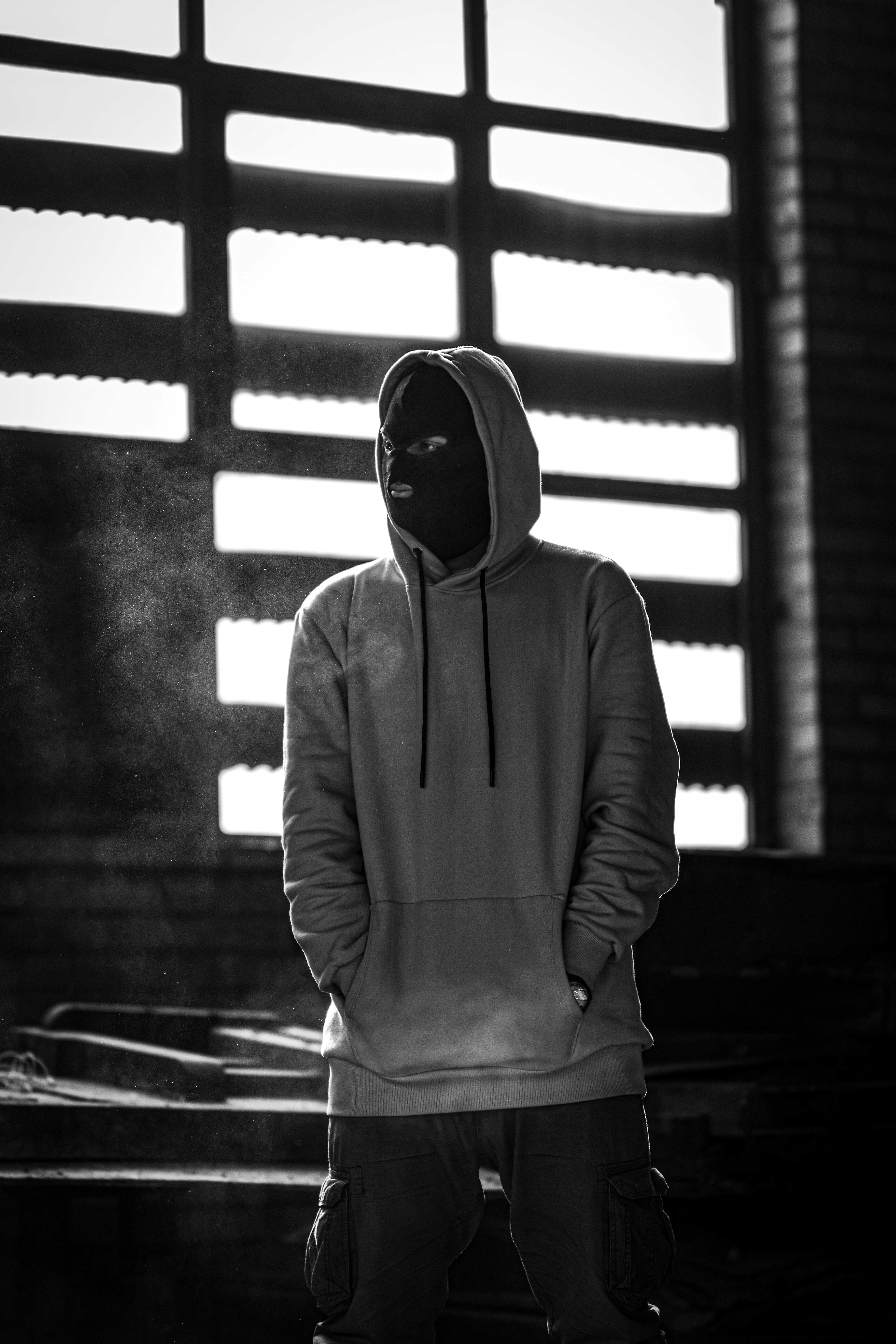 Hooded Silhouette Under a Grid of Backlit Windows