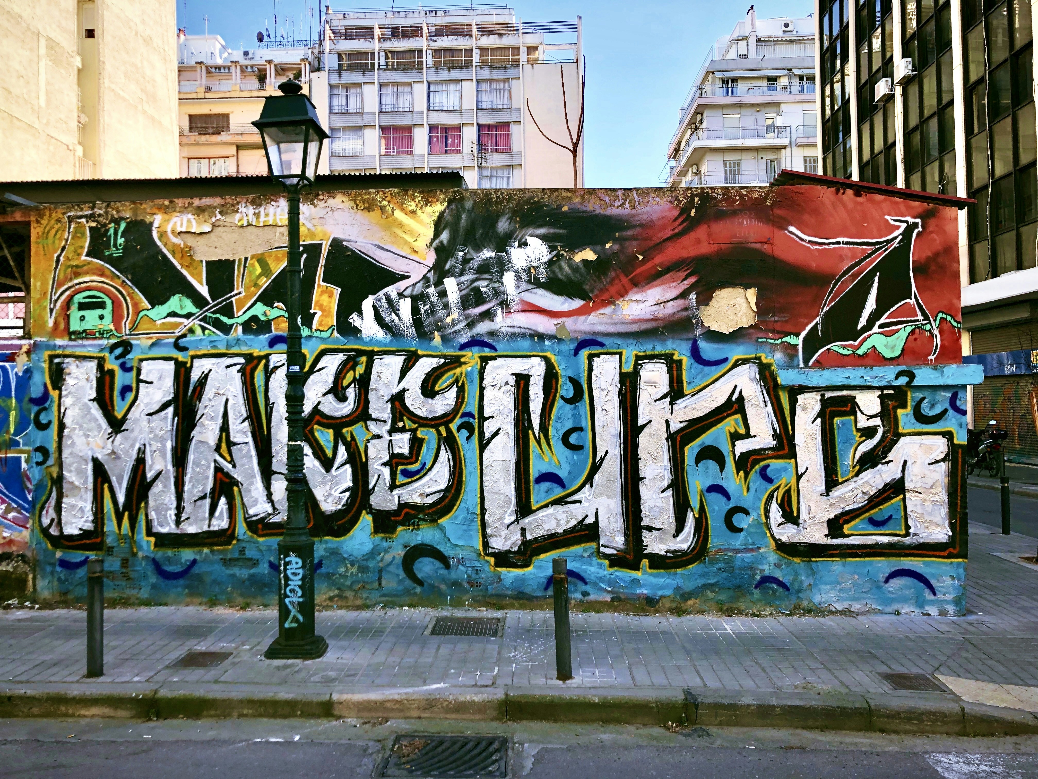 Urban Glyphs Across a Blue Brick Wall: White Letterforms Meet a Red Dragon