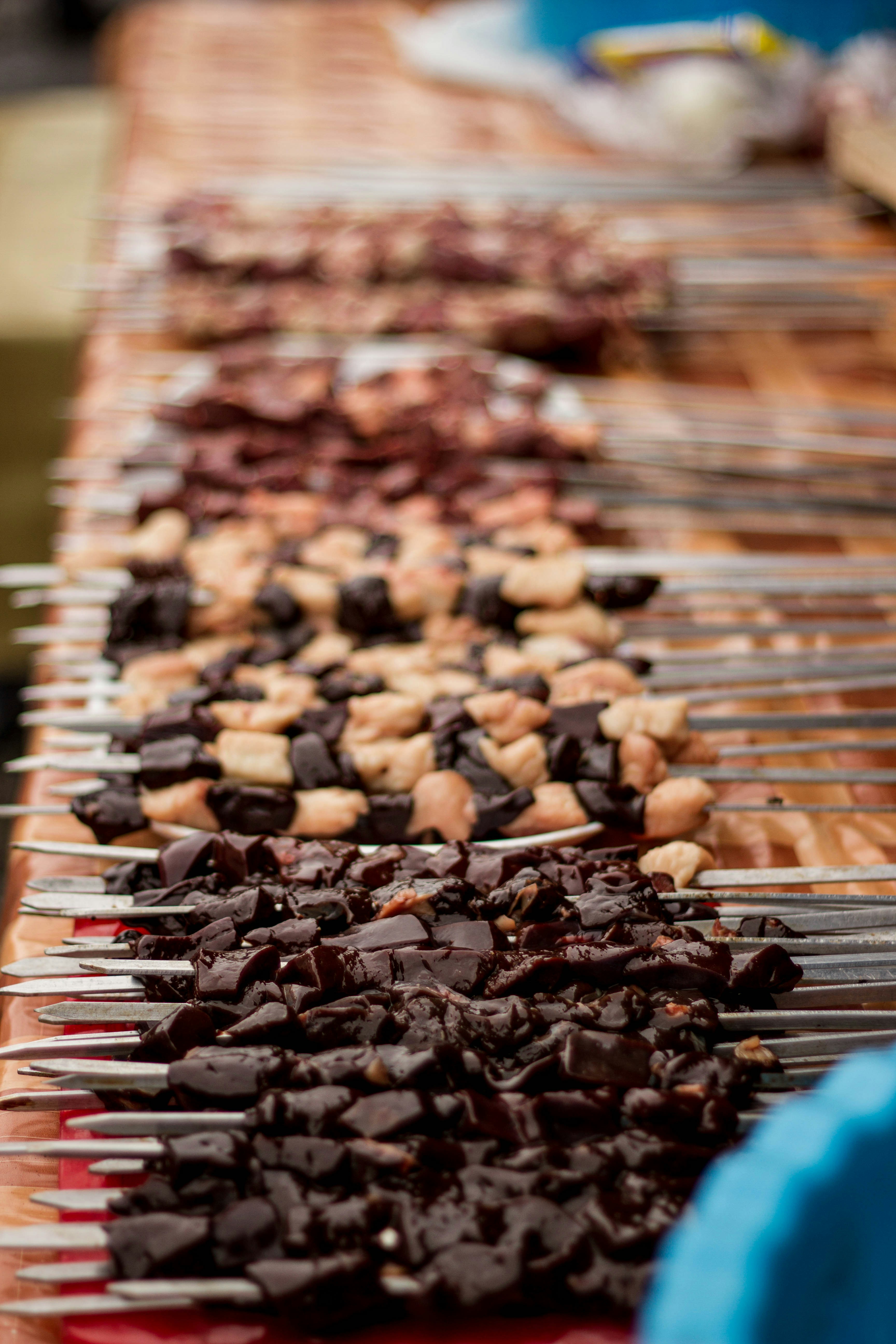 Assorted skewers of meat and vegetables arranged neatly on a wooden table, highlighting a variety of textures and colors.