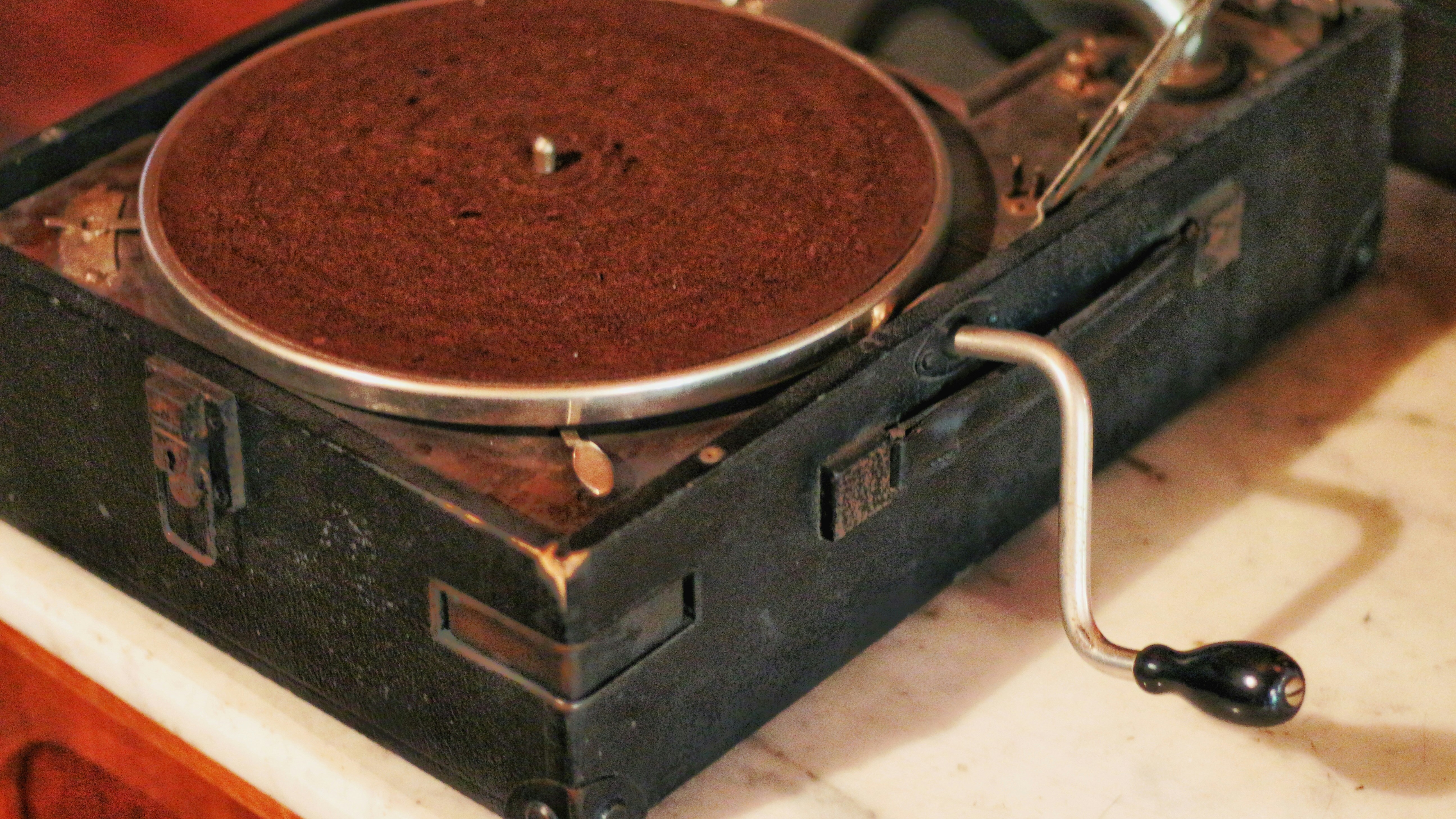 Dusty Stage: A wind-up portable turntable resting beside its weathered case
