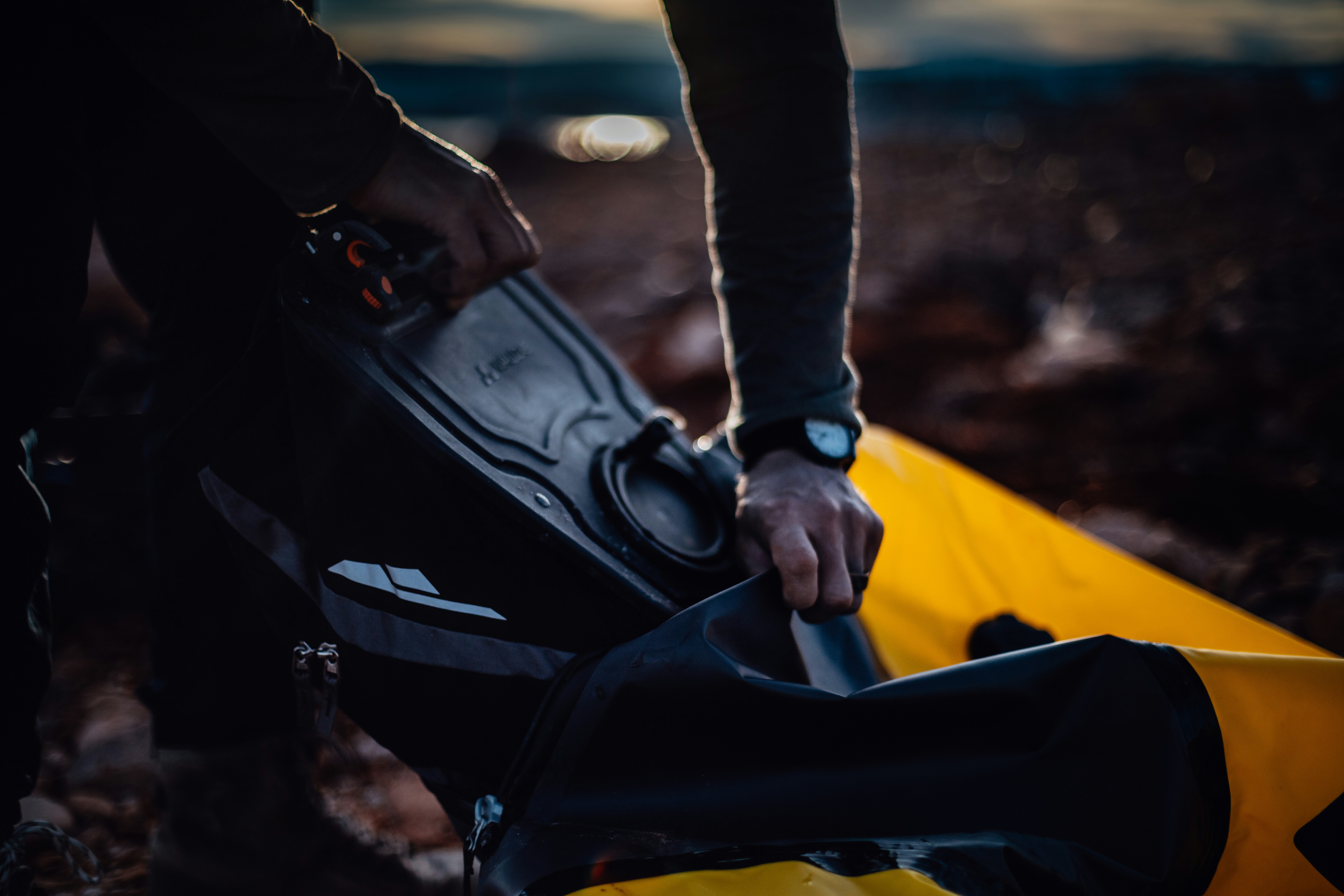 Dusk Craft: Hands Securing Gear on a Bright Yellow Kayak