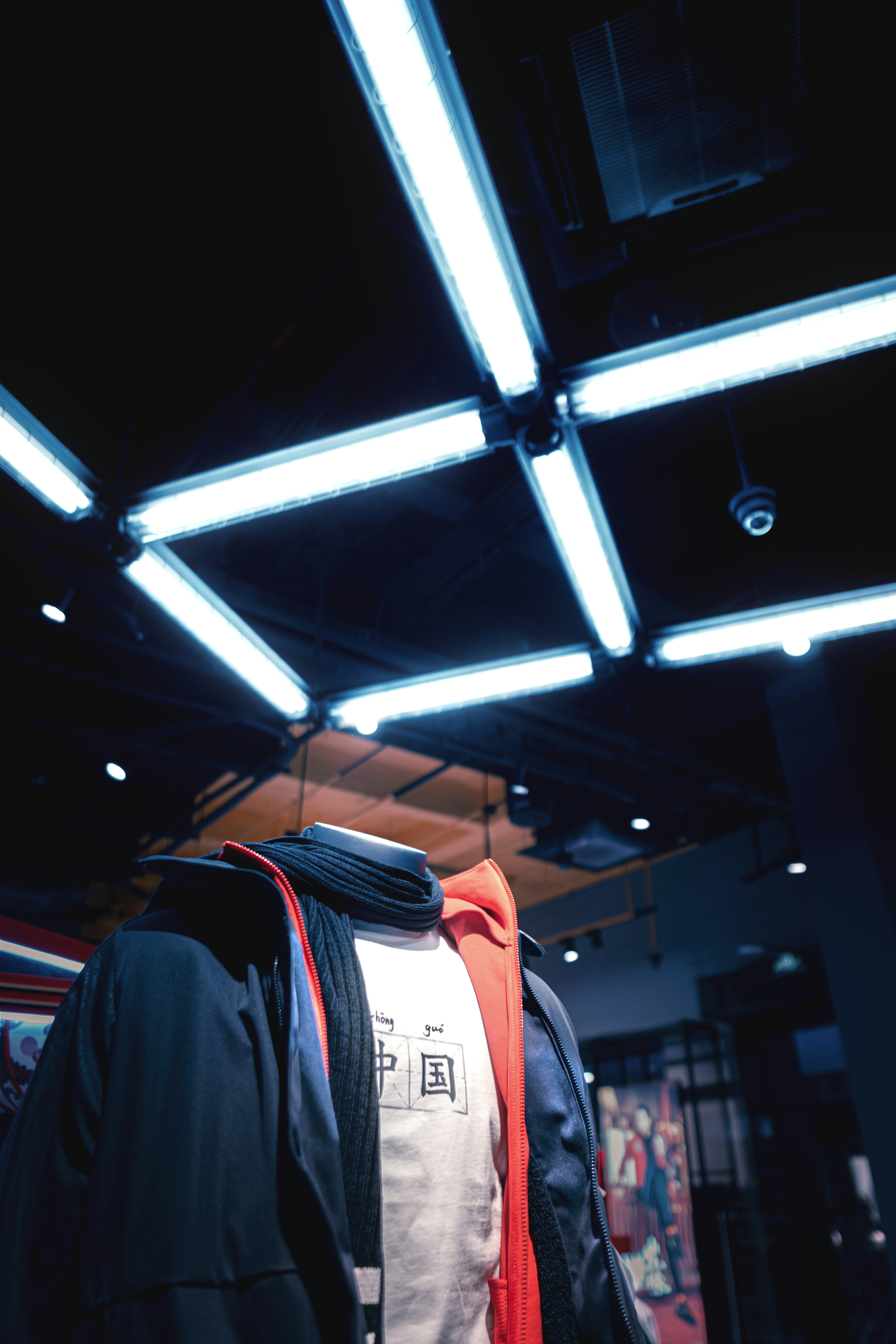 A headless mannequin showcases a stylish outfit under vibrant overhead lighting, emphasizing contemporary fashion trends.