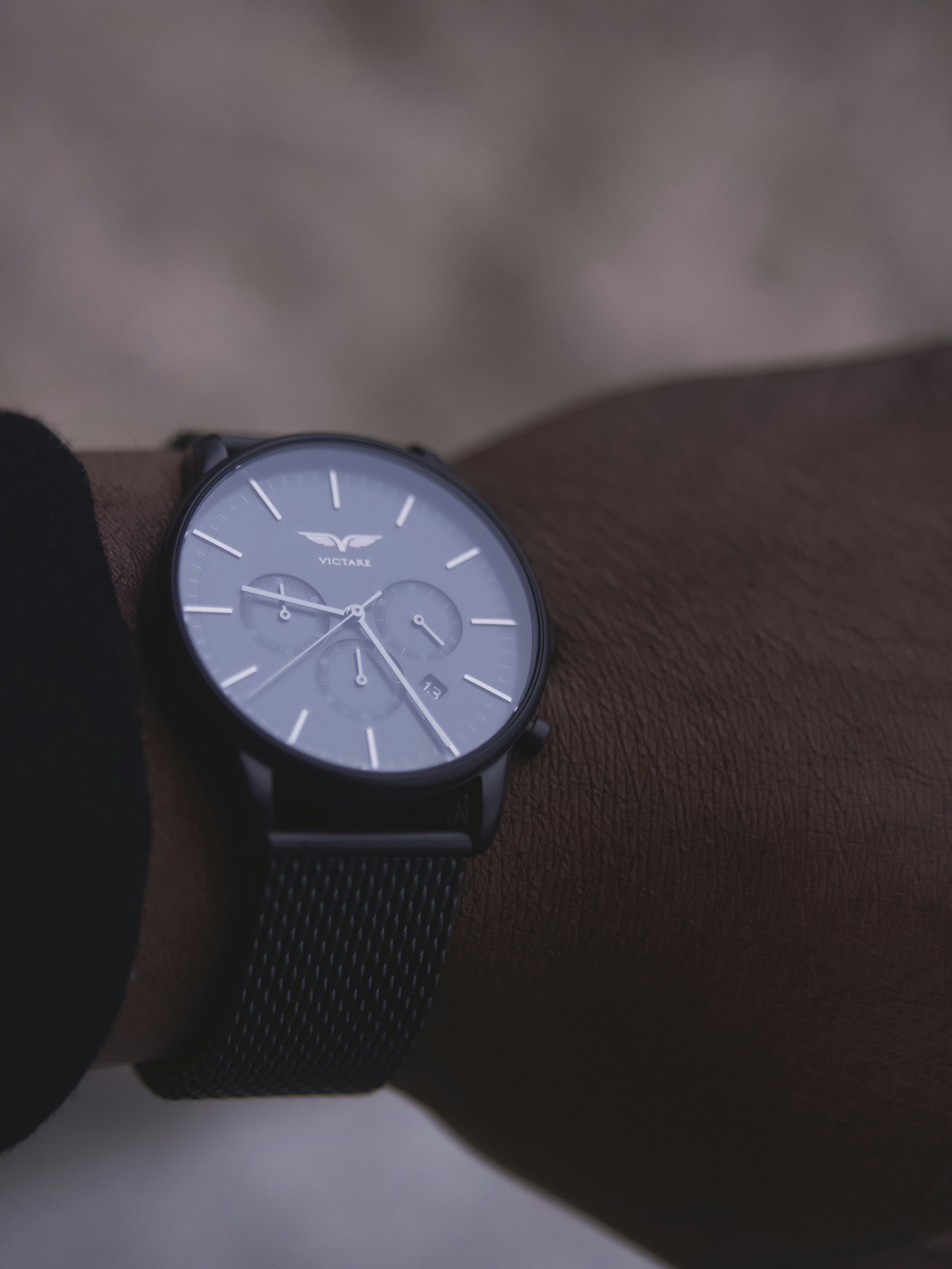 Close-up of a sleek black watch resting on a wrist, showcasing its minimalist design and intricate details.