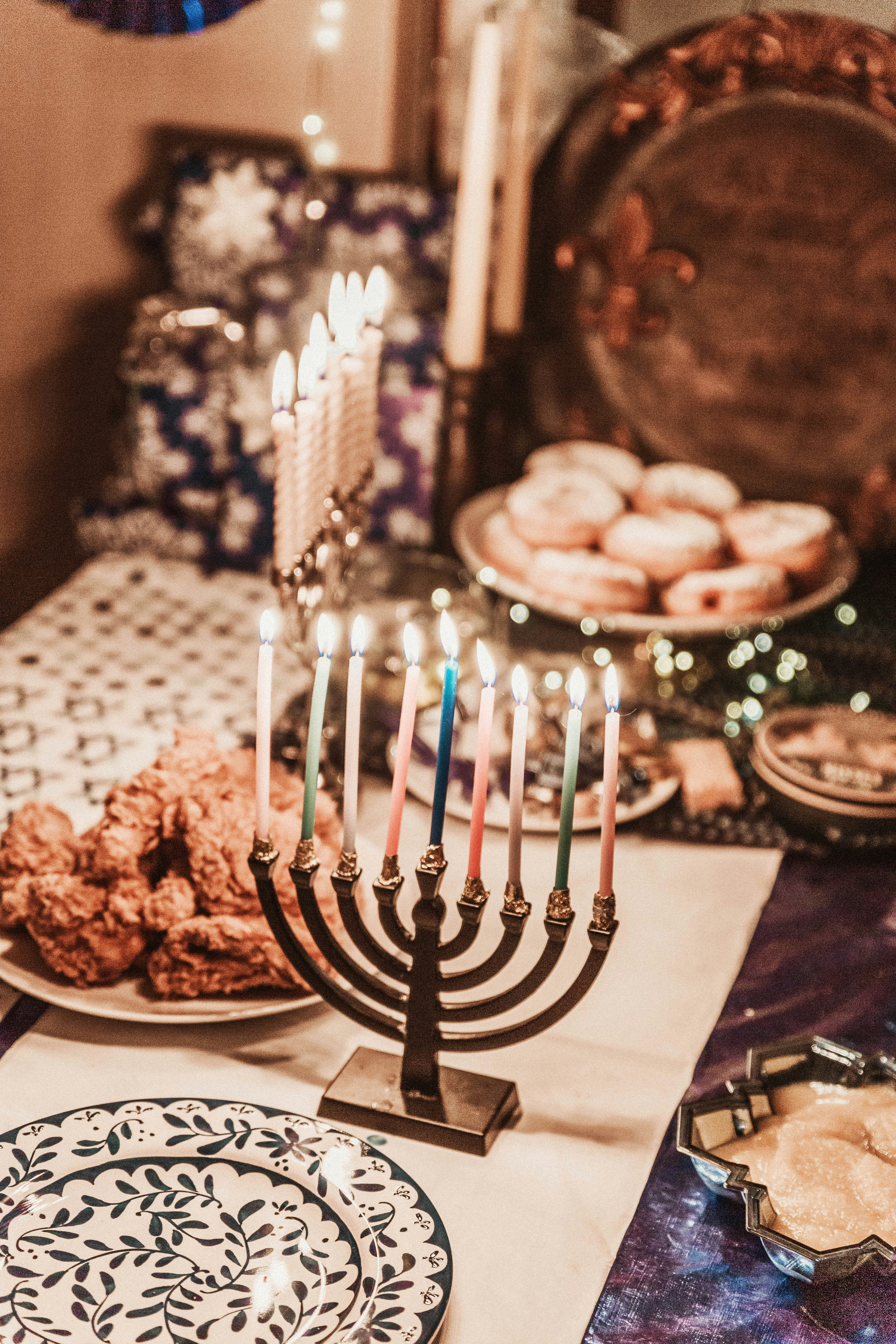 Candlelit Hanukkah Moment: A Table Packed with Treats and a Centered Menorah