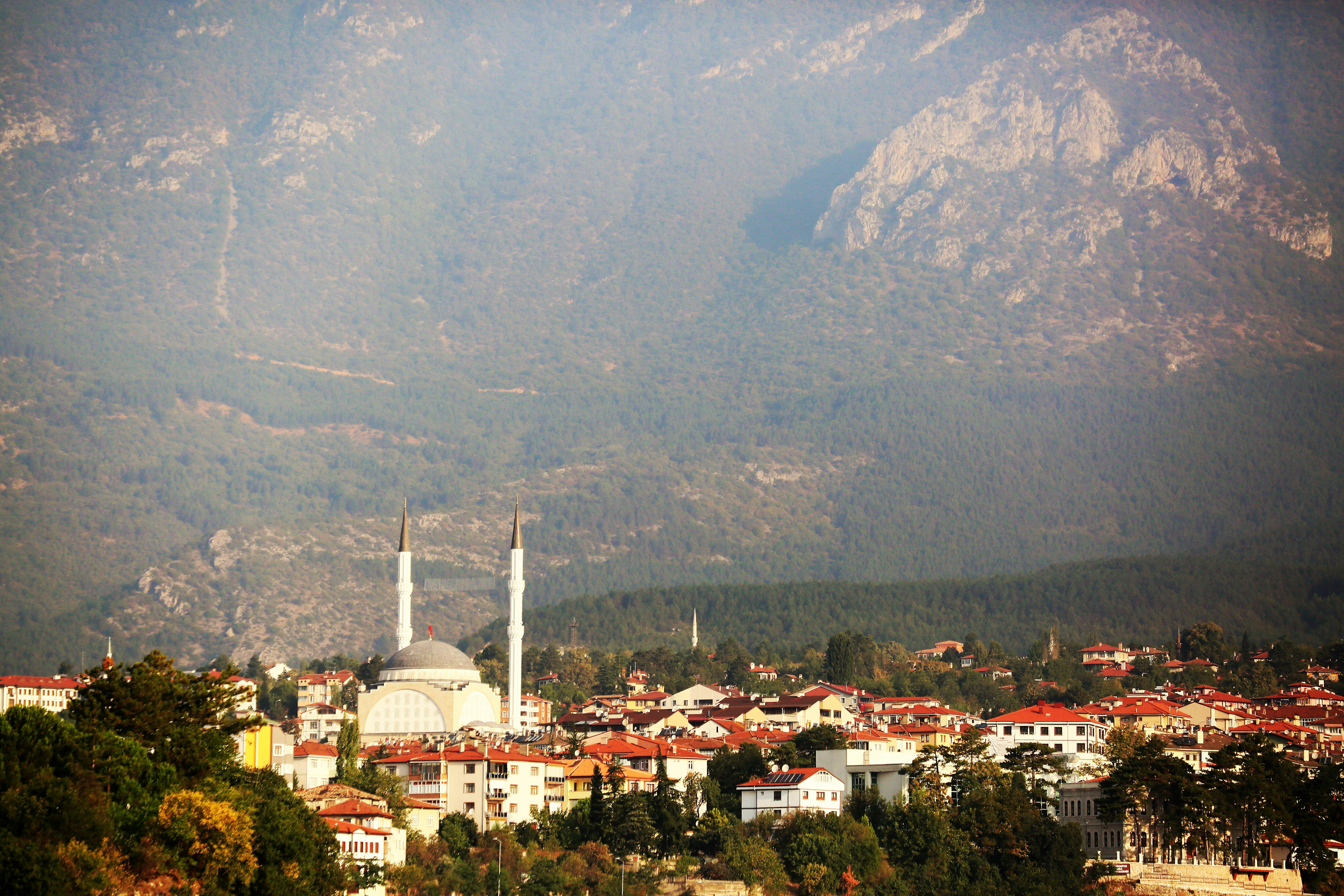 Townscape with a mosque nestled at the base of mist-covered mountains.