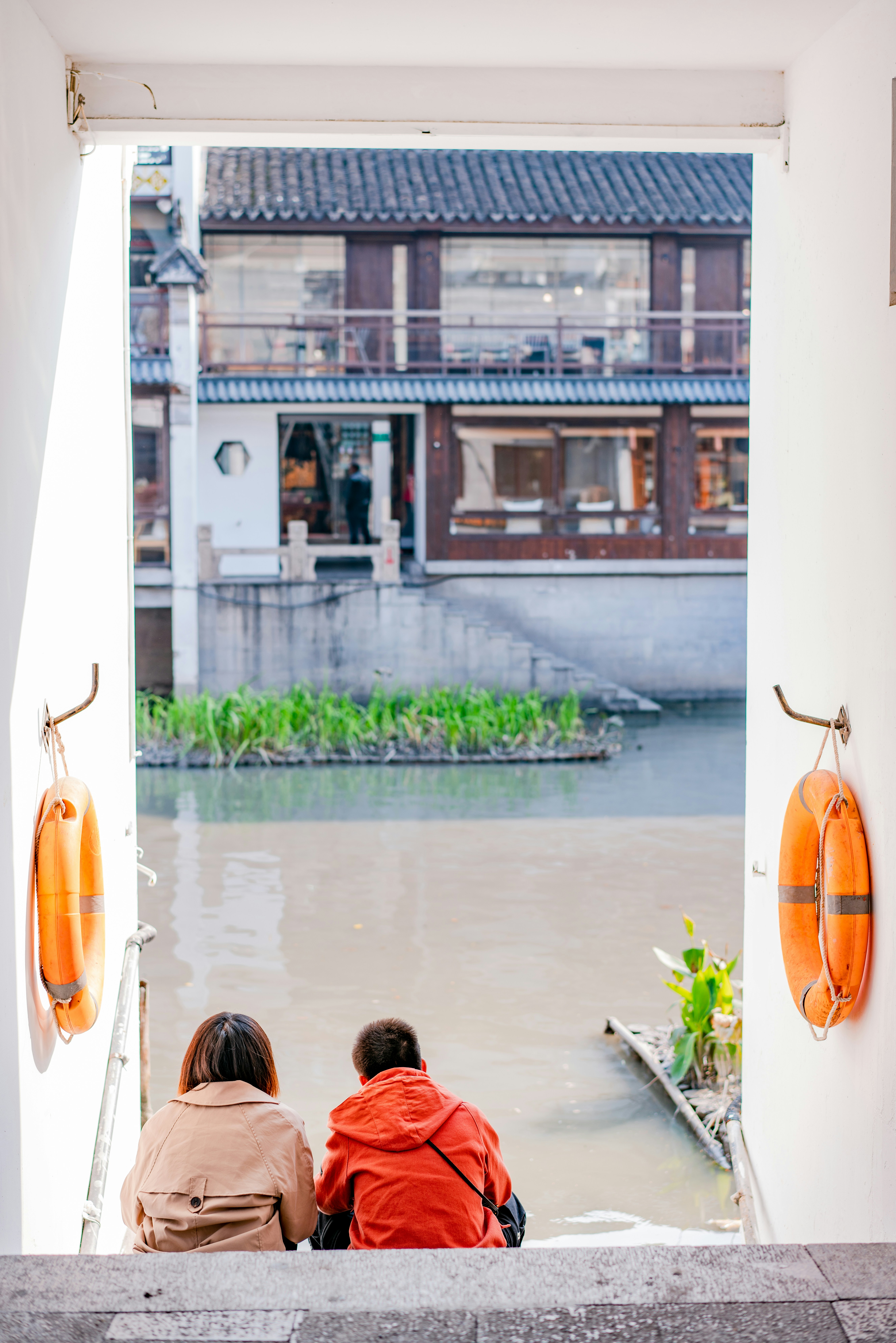 Threshold of Light: Two Travelers by a White-Walled Canal