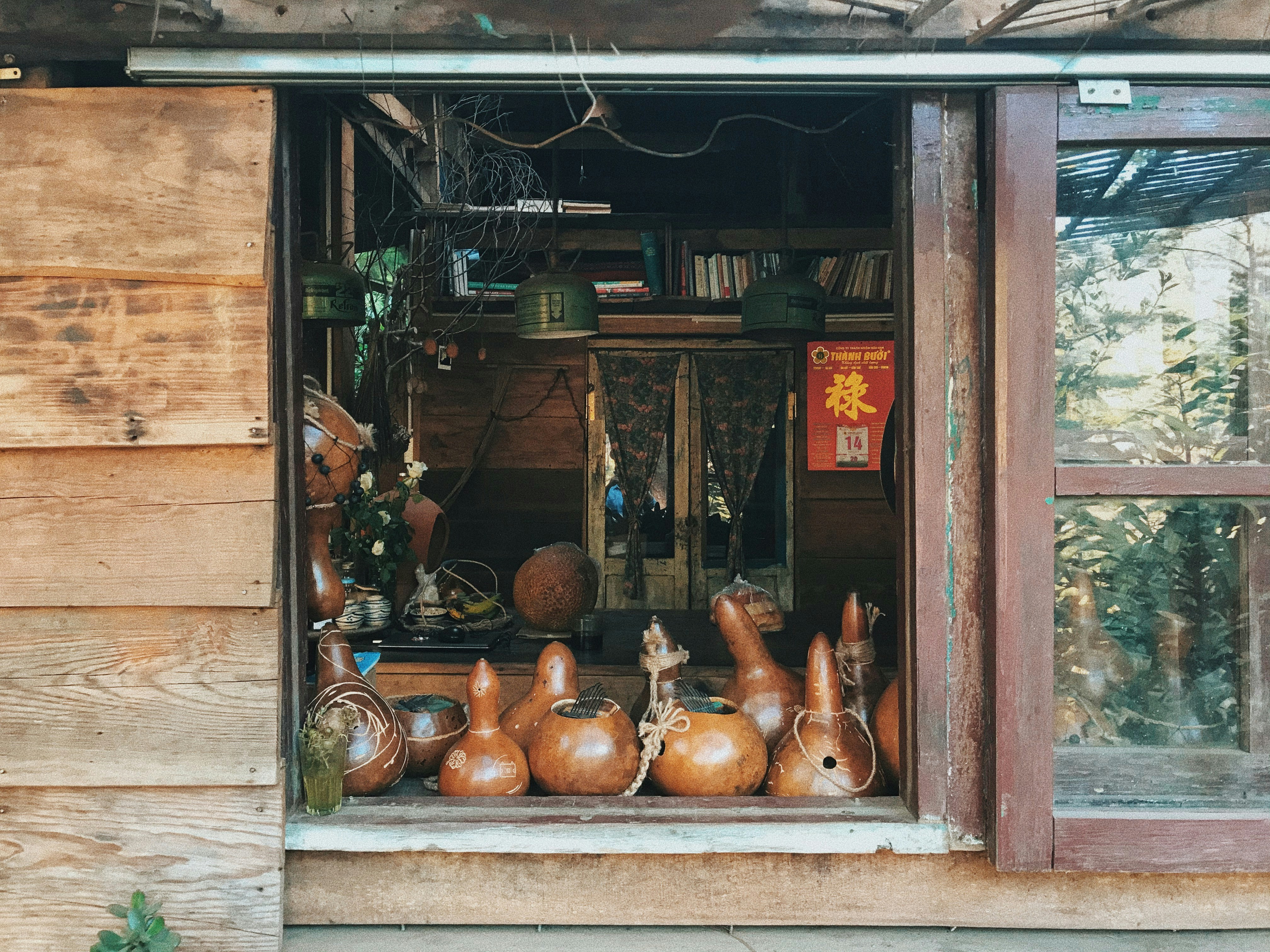 Rustic window showcasing an array of handcrafted gourd vessels and decorative elements, reflecting cultural artistry and history.